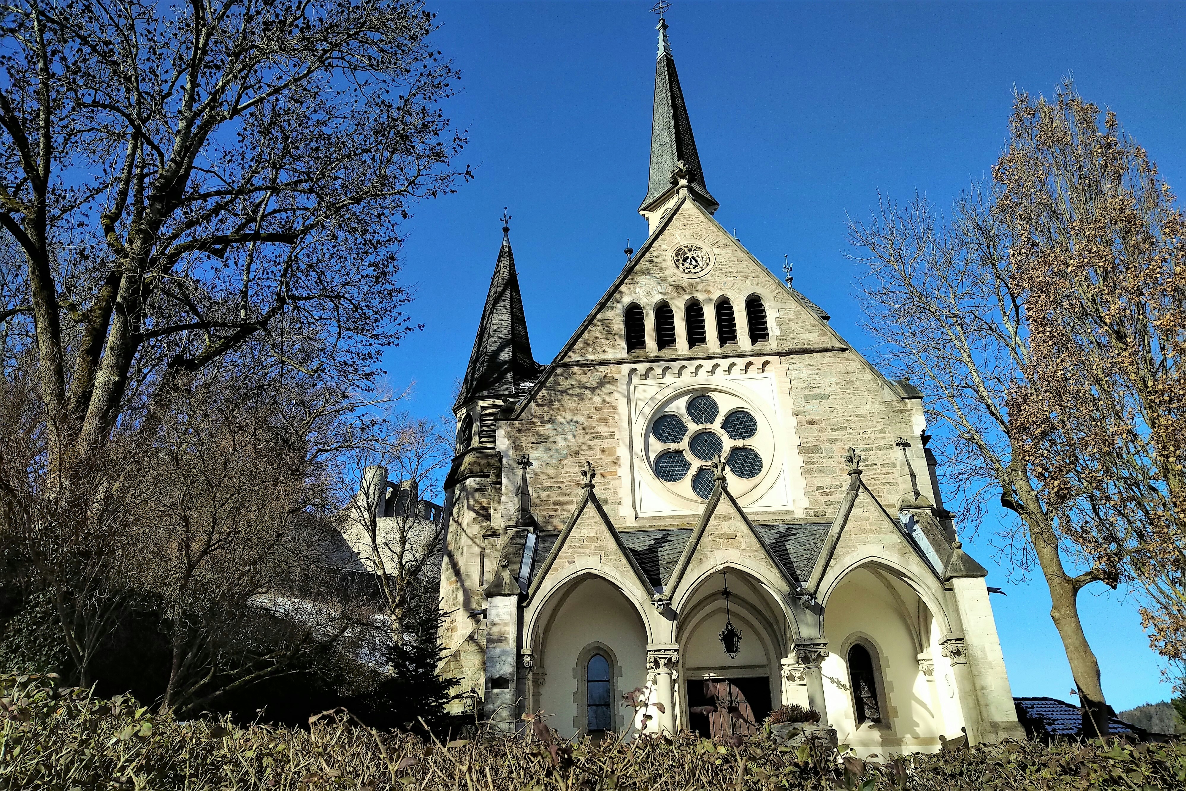 Historic church with pointed arches and a central rose window beneath a vibrant blue sky.
