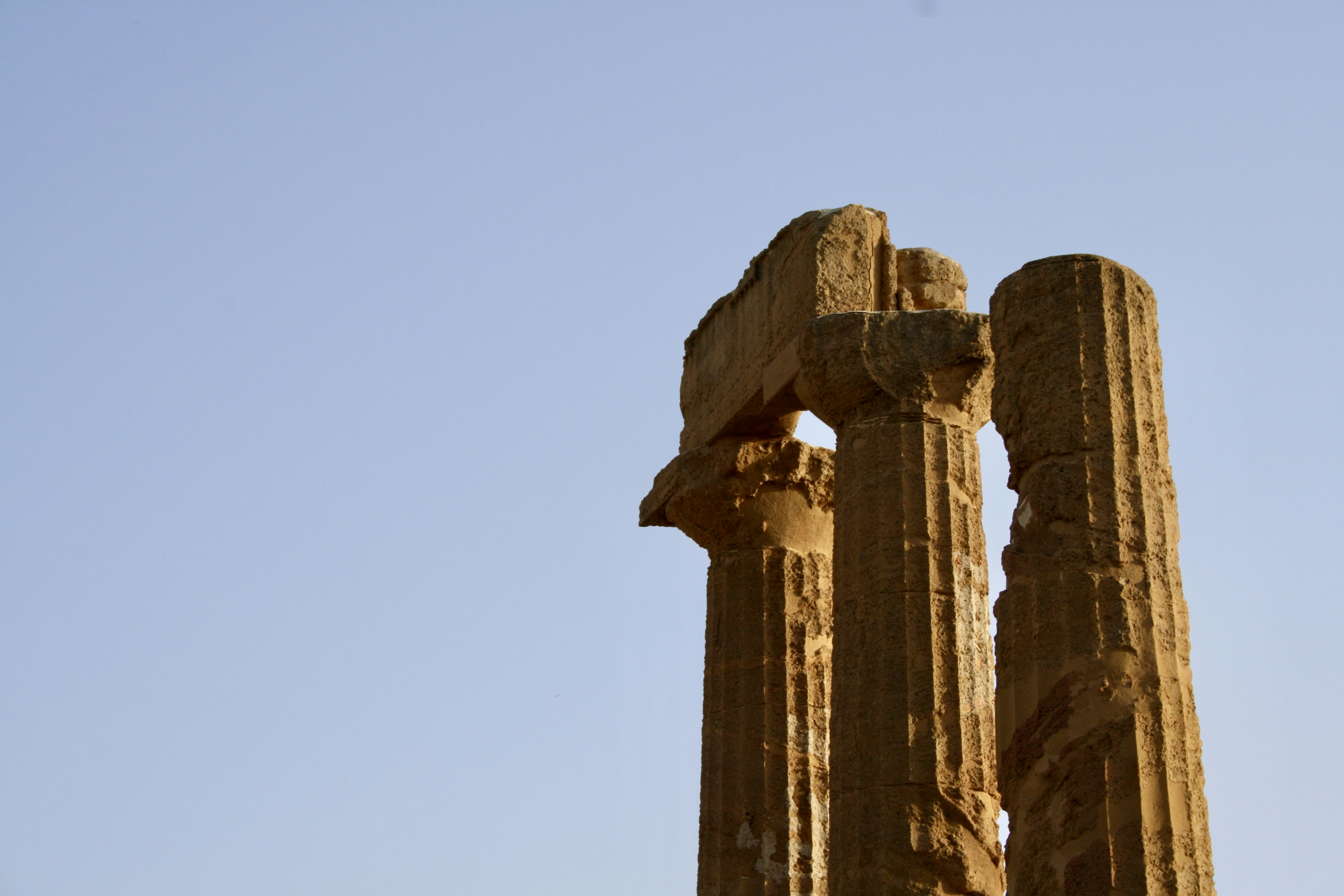 Ruins of towering stone columns under a clear blue sky.