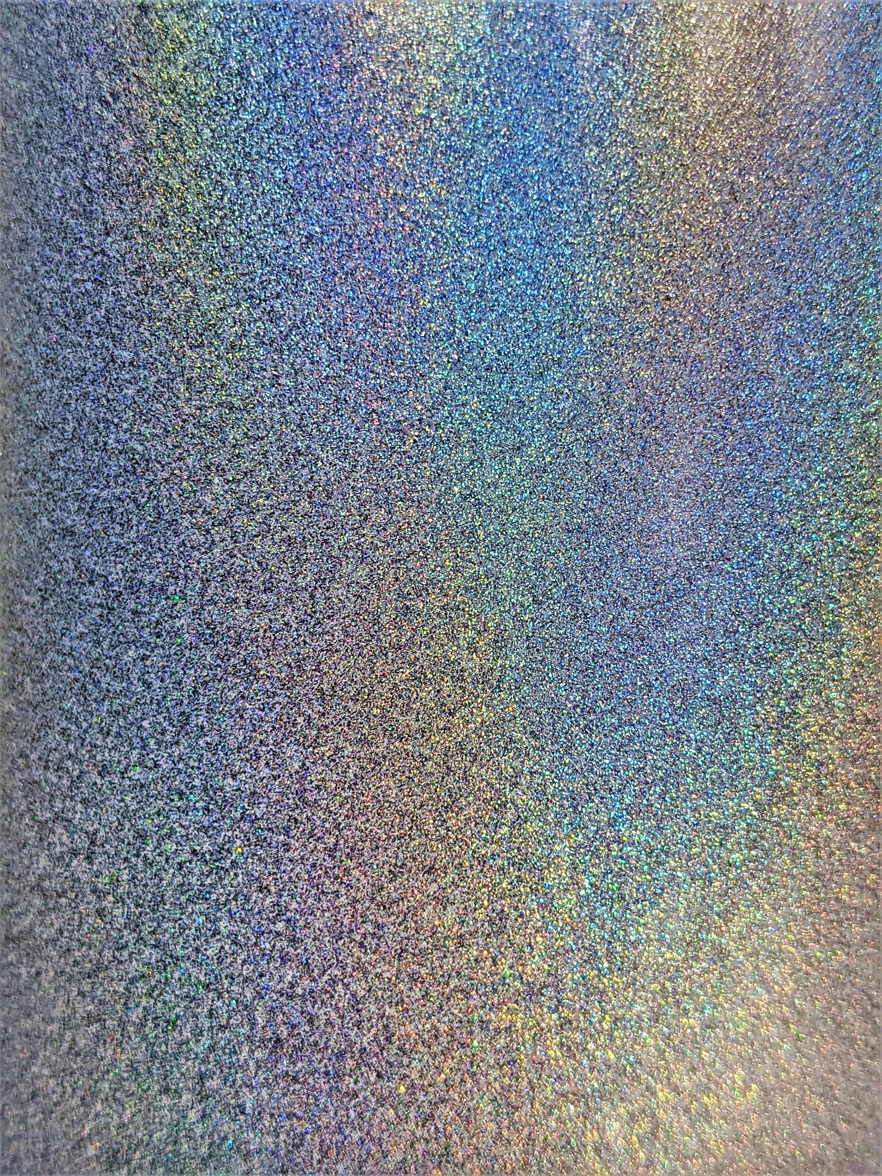 Close-up of a shimmering surface displaying a spectrum of colors and fine textures. The interplay of light creates a mesmerizing visual effect.