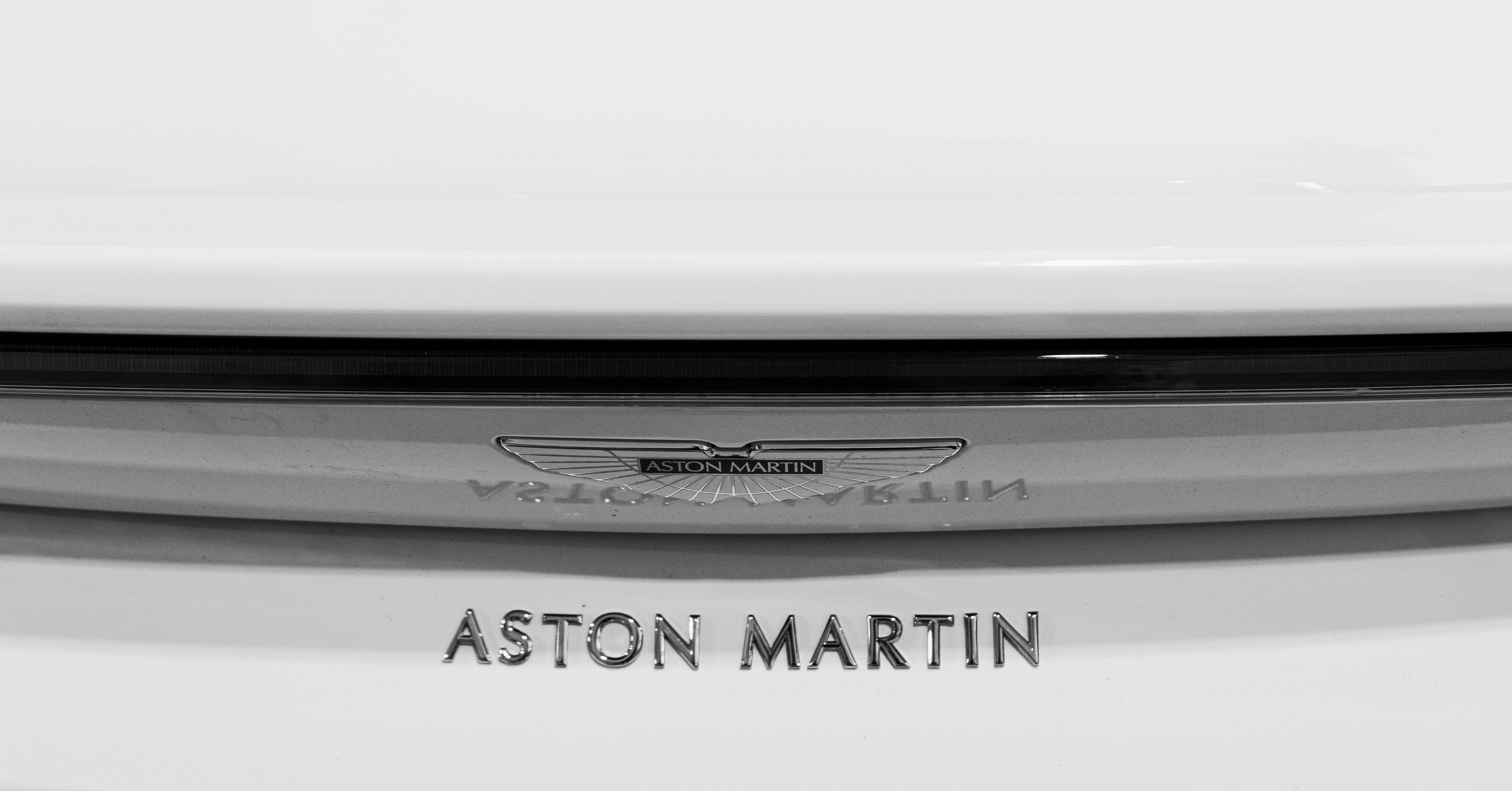 Emblem and Script: The Aston Martin Badge Framed by Car Belle Époque Minimalism