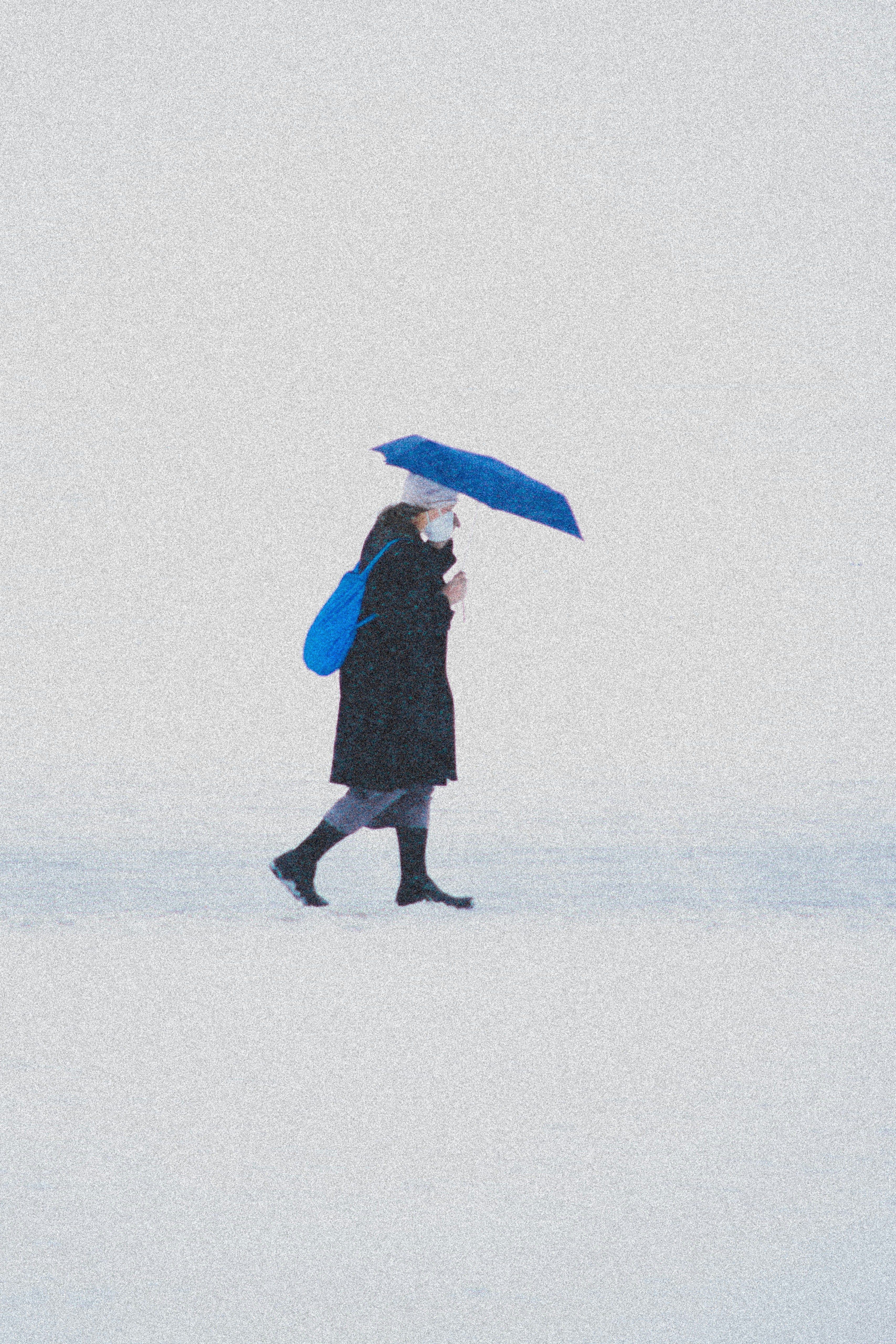 A woman walking through a white winter world with a lot of snow in Stuttgart, Germany | woman in blue coat holding umbrella