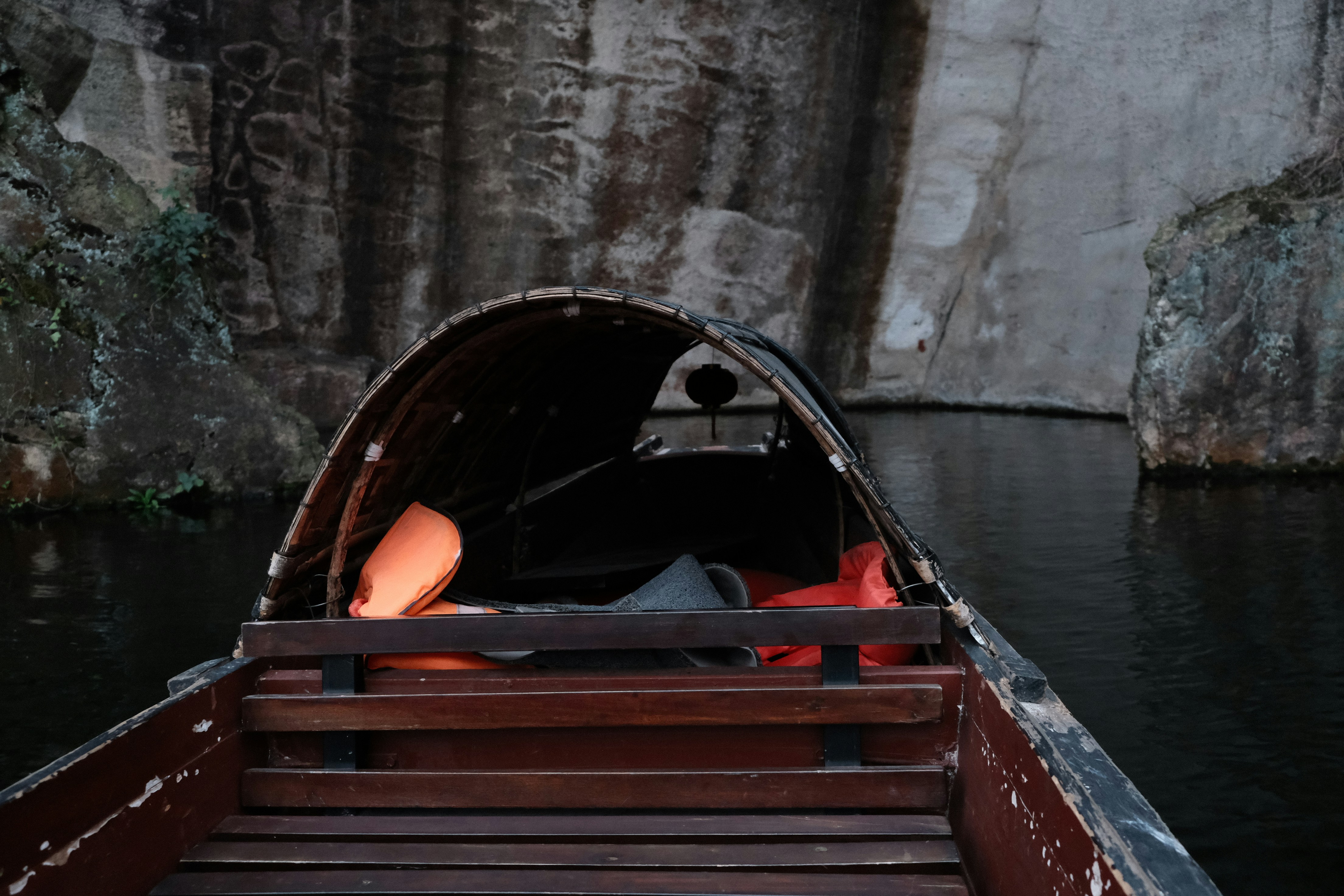 Rowboat in a Shadowed Gorge: Orange PFDs Rest Amid Dark Canyon Walls