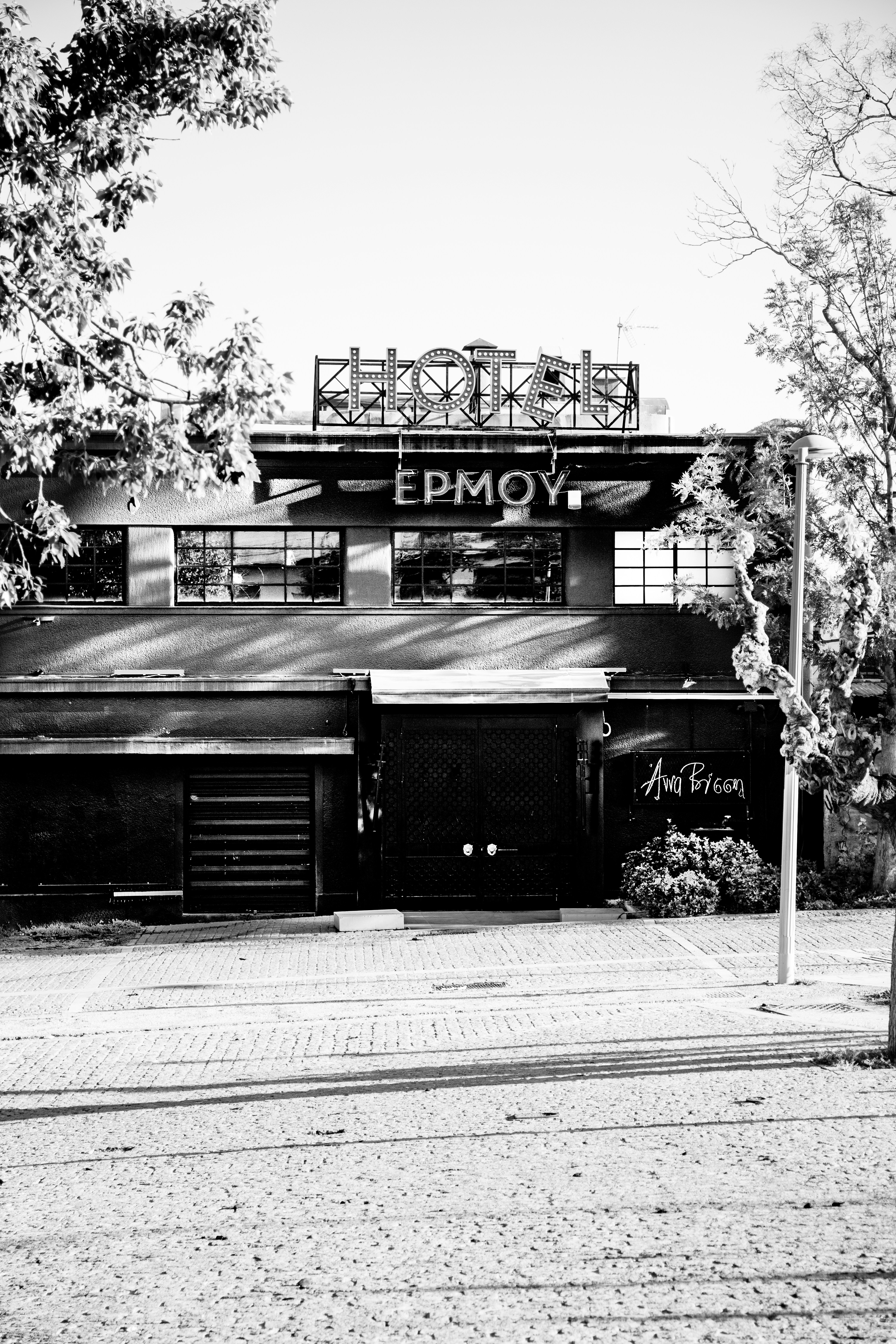 Black-and-white photograph of a mid-century hotel façade with a large sign atop and a dark central doorway.