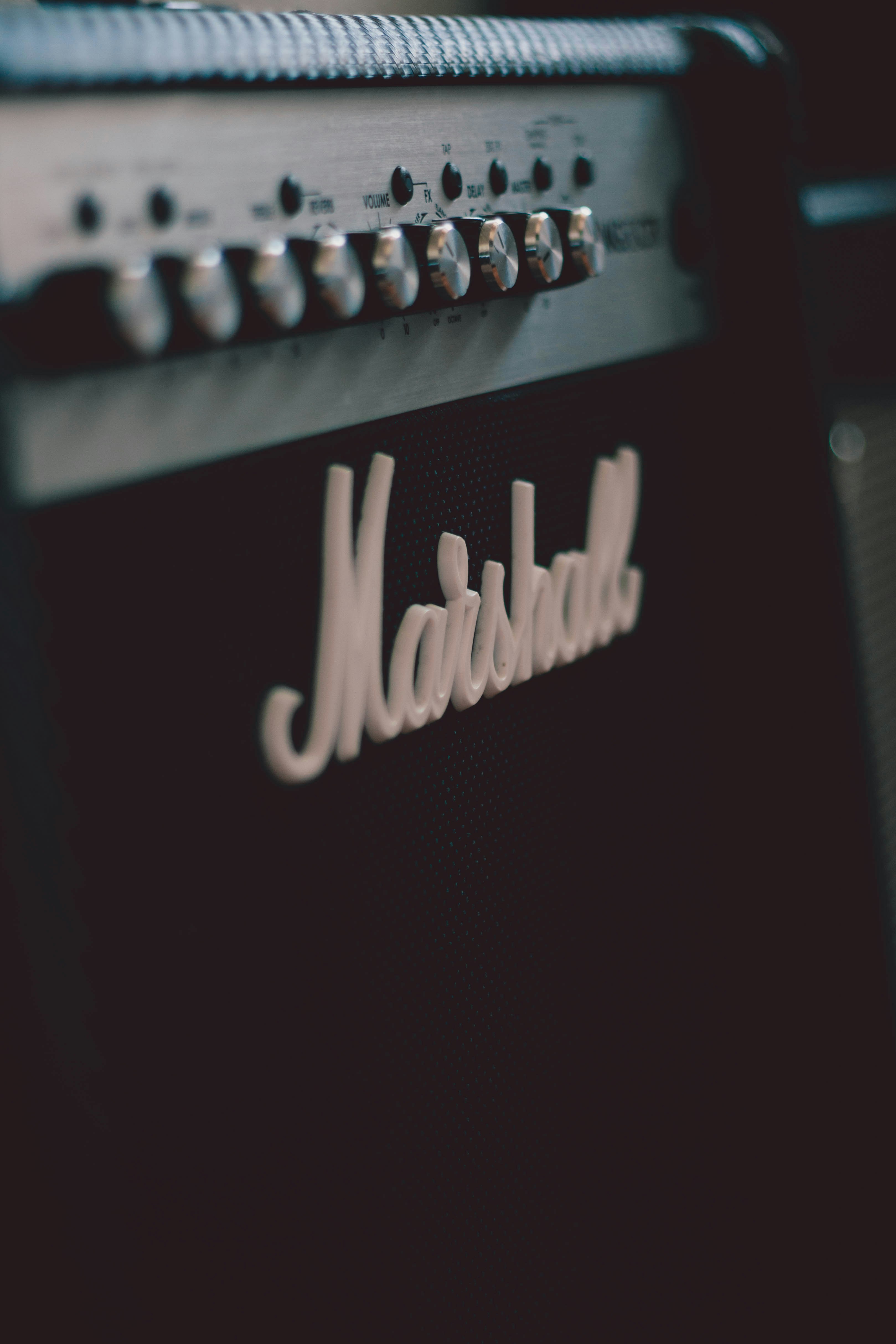 Close-up of a Marshall guitar amplifier showcasing its iconic logo and control knobs. The focus highlights the craftsmanship and design elements of the equipment.
