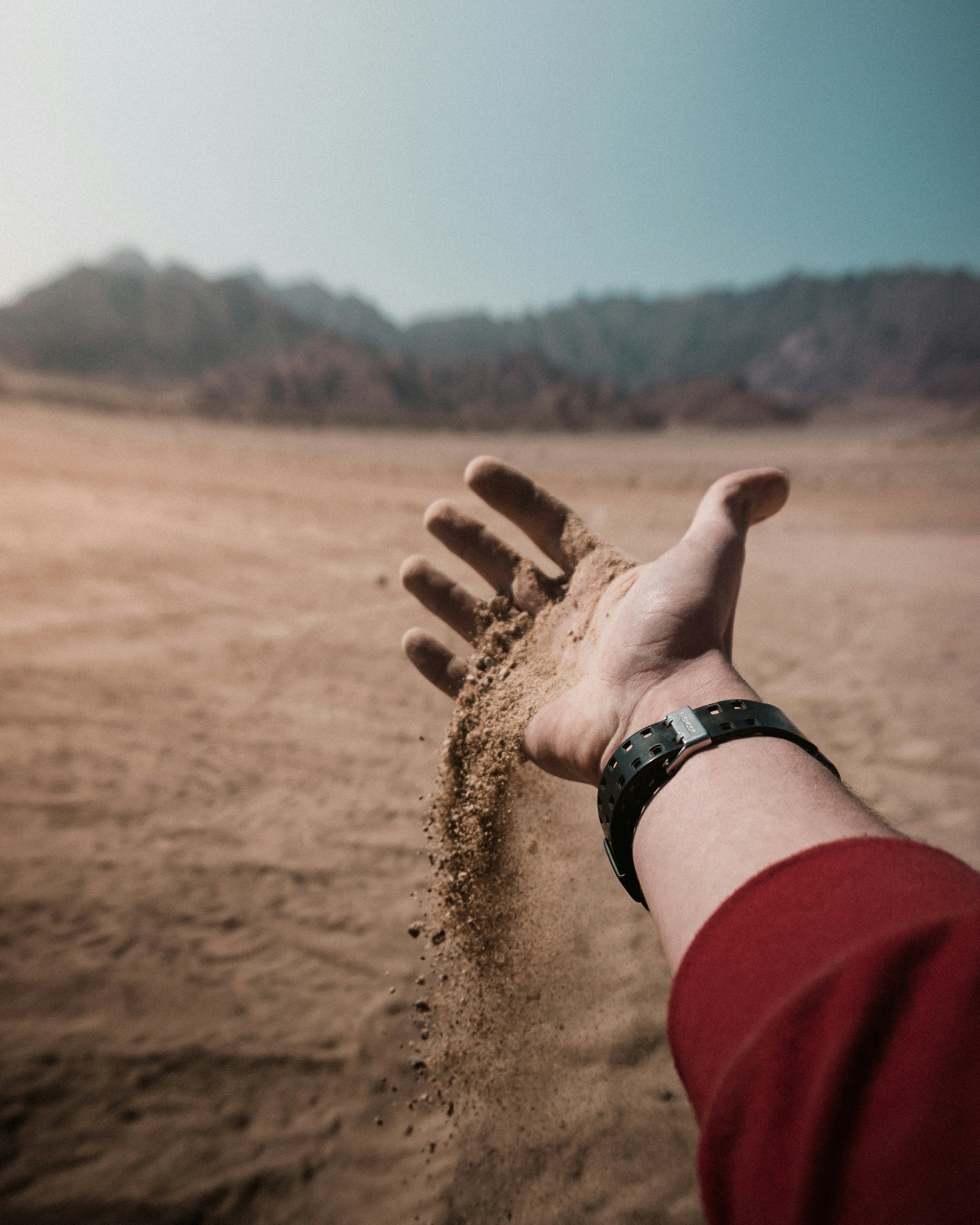 Desert Release: A Hand Sifts Sand Across a Quiet Dune Field