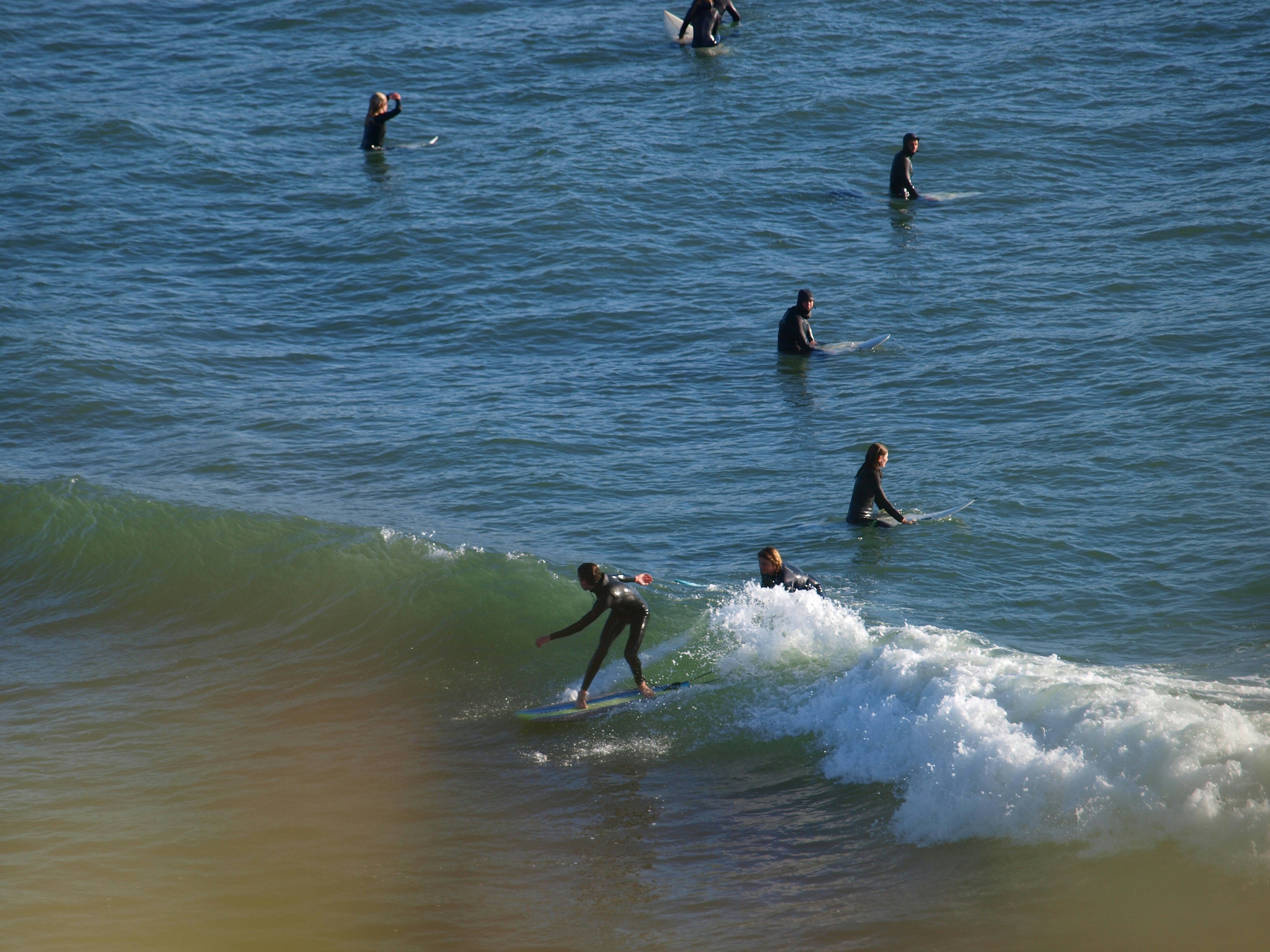 Surfers skillfully navigating the surf, capturing the essence of ocean adventure and camaraderie. The scene showcases the thrill of riding waves in a vibrant coastal setting.