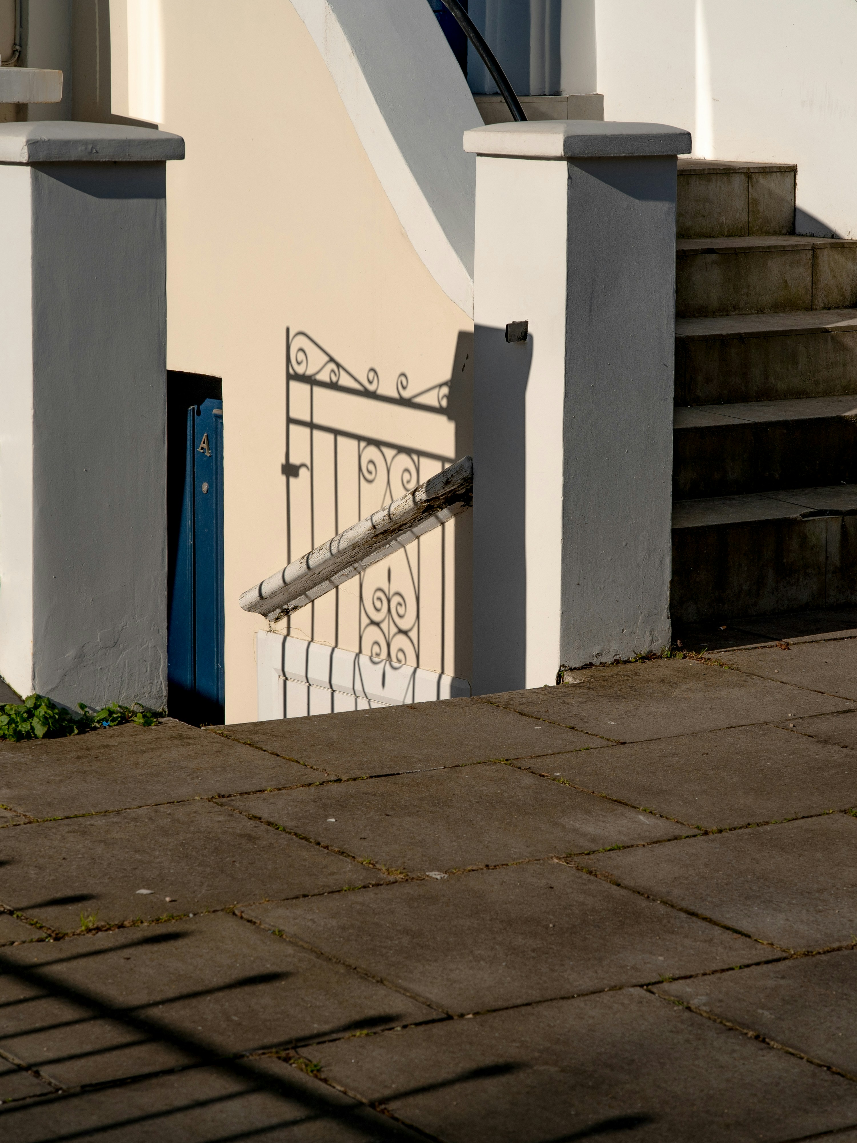 Sunlit Ironwork by the Stair: A Quiet Facade Study