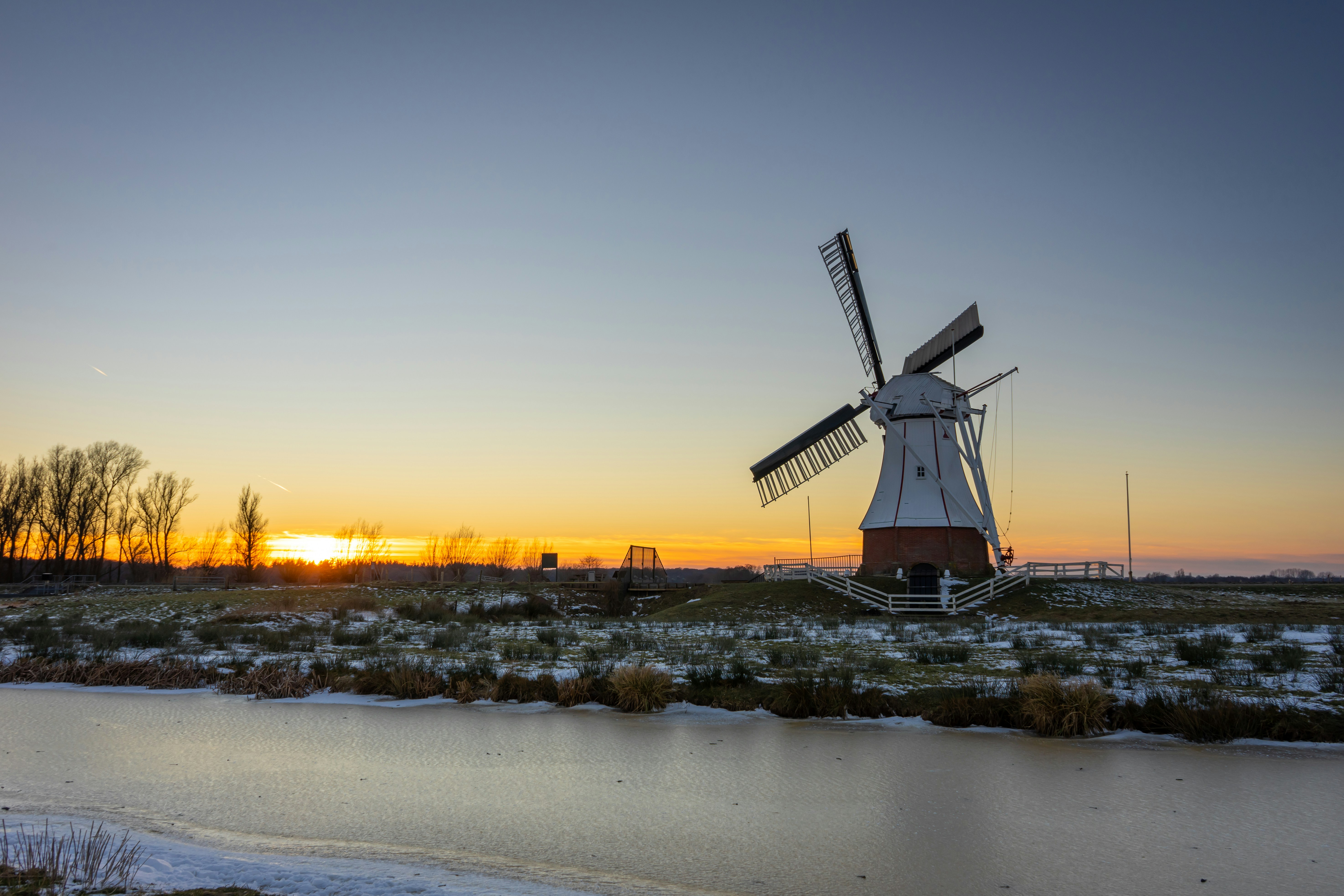 Sunset Sentinel: A Windmill Framing the Quiet Canal