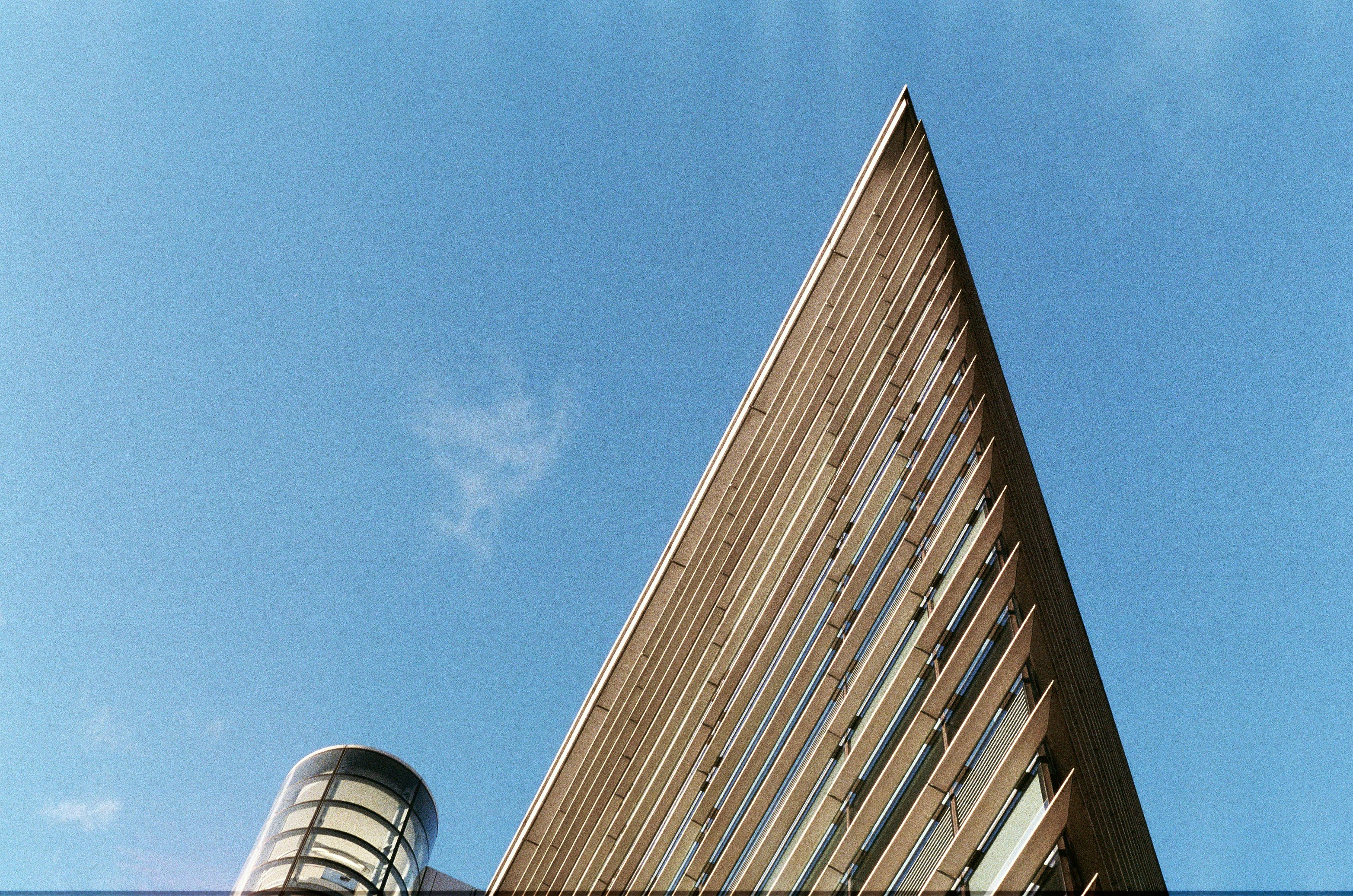 Angular building facade reaching towards the sky, showcasing modern design elements against a clear blue backdrop.