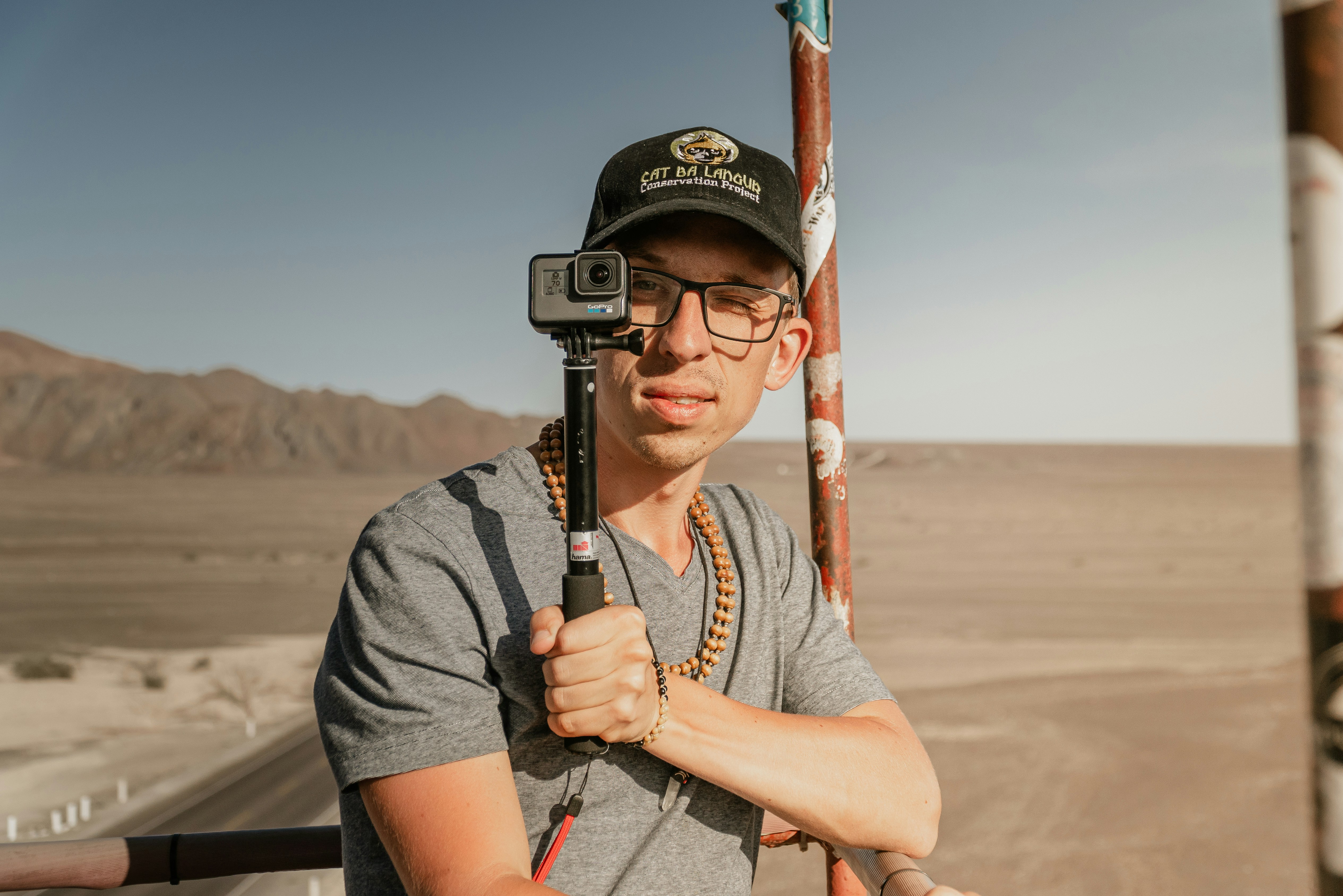 Individual holding a camera on a tower overlooking a vast desert landscape. The scene captures the spirit of adventure and exploration.
