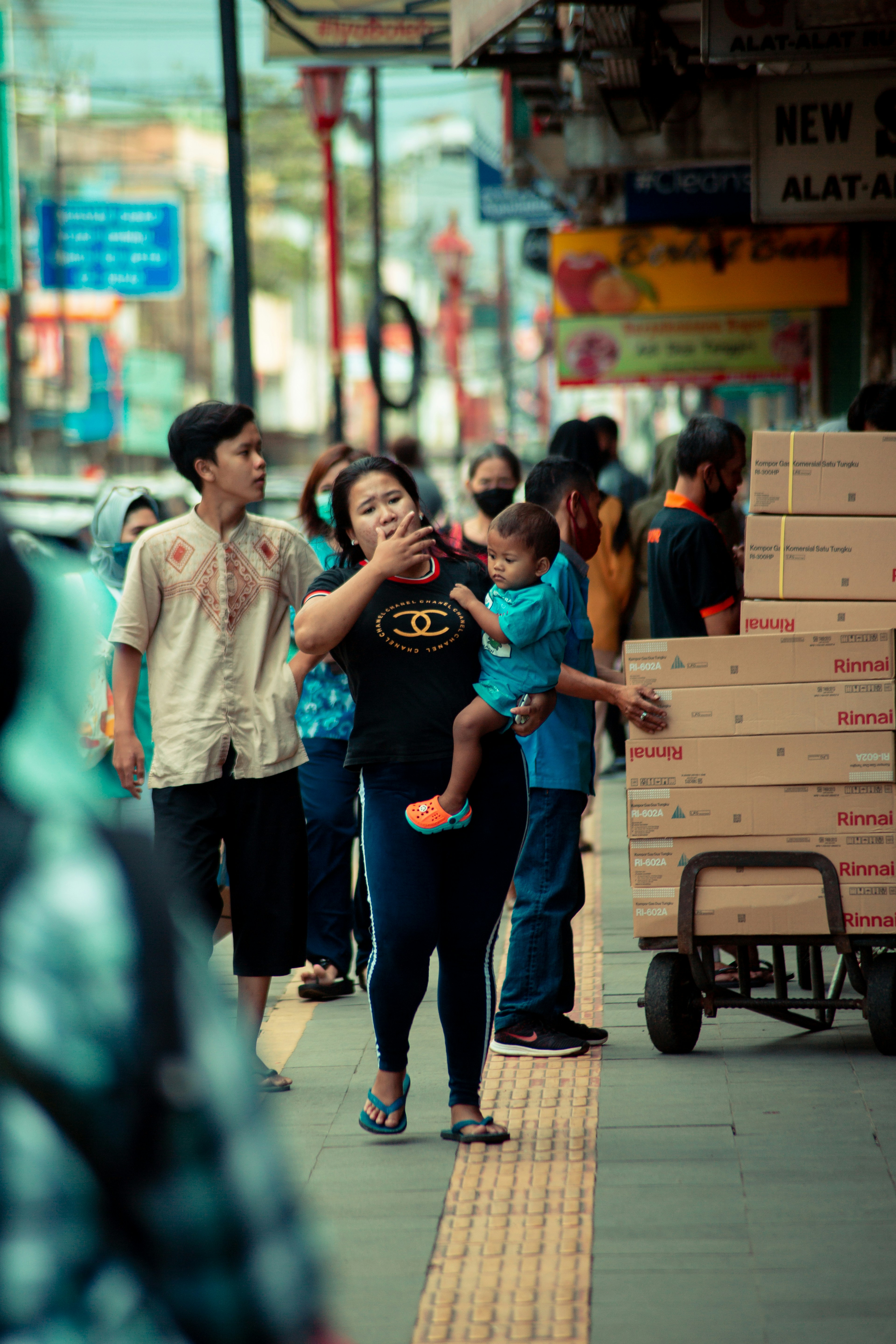 Between Signs and Steps: A Mother with Child in a Busy Market Corridor