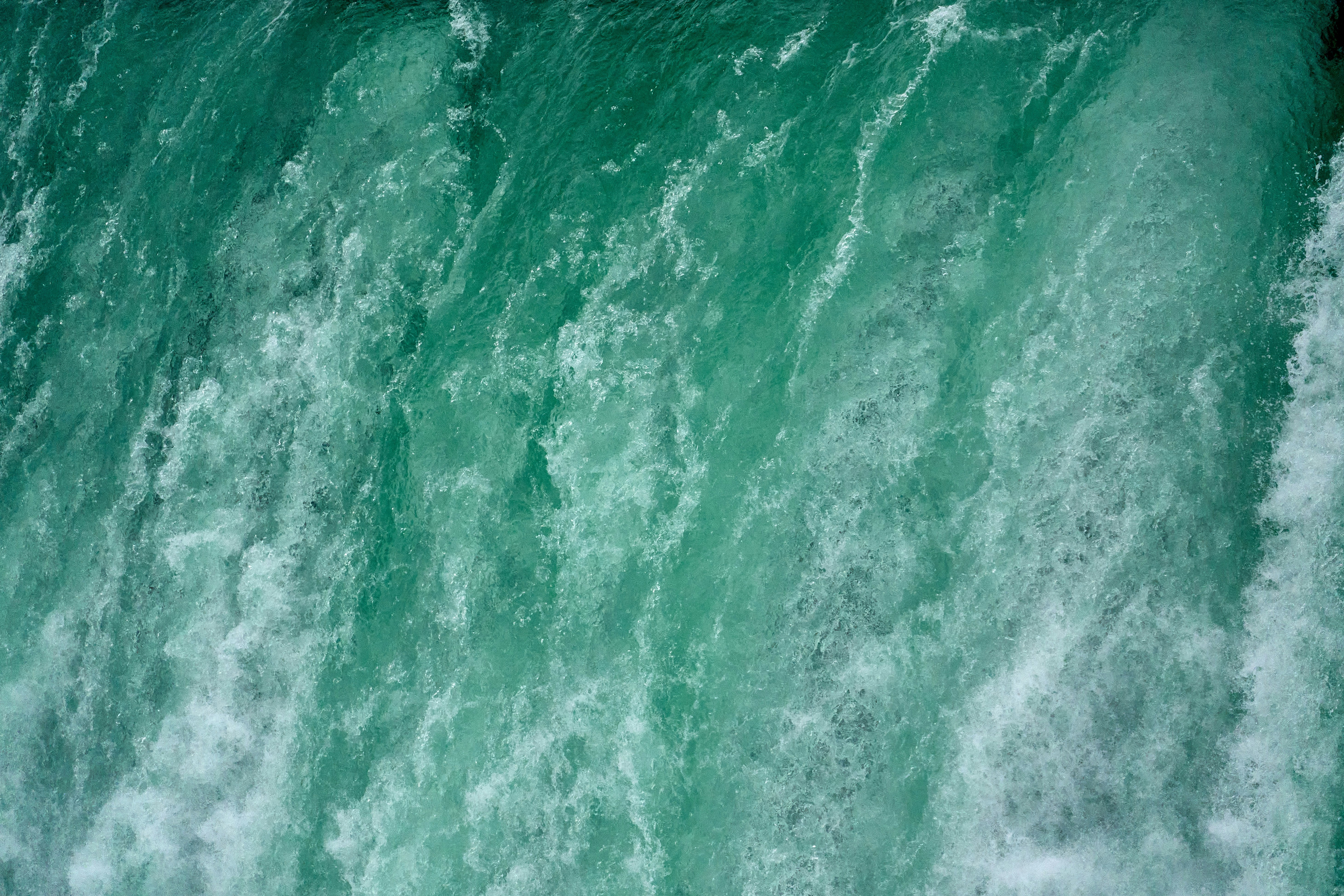 Vibrant turquoise water cascading in rhythmic waves, showcasing the dynamic movement of a waterfall.