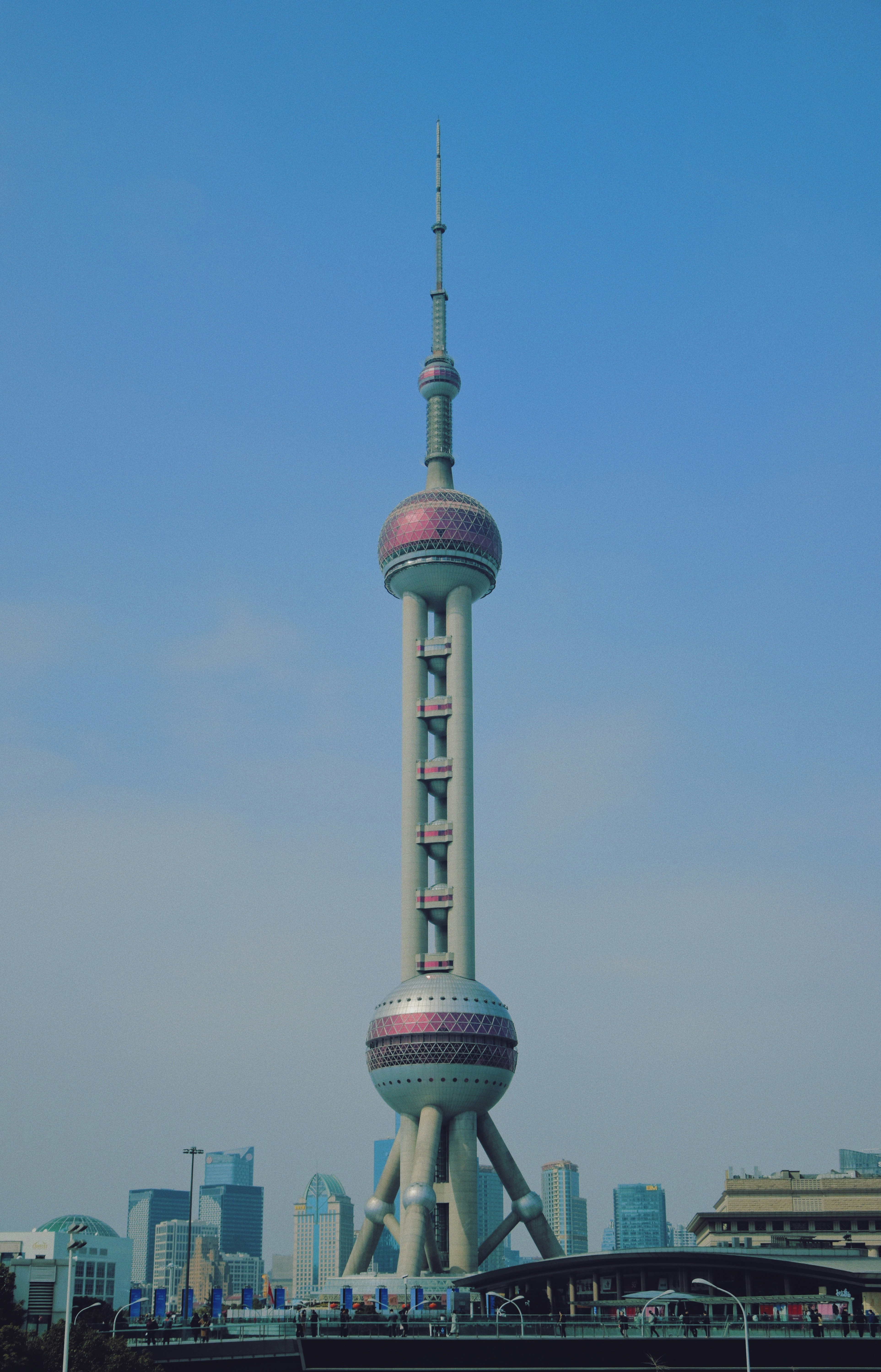 Oriental Pearl Tower rising majestically against a clear blue sky, surrounded by the modern skyline of Shanghai. 