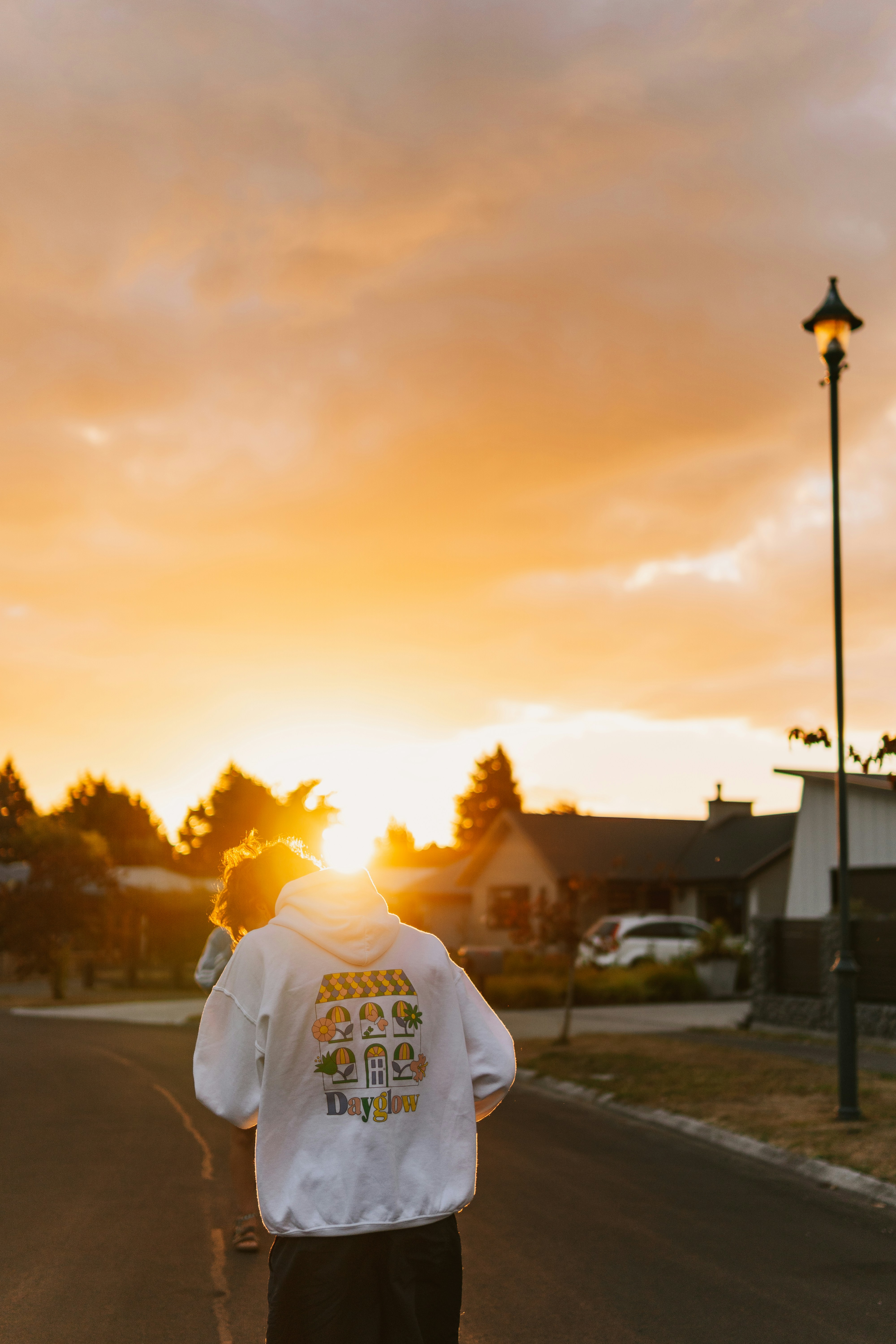 Golden Hour Pause: Hooded Figure Stands in a Quiet Suburban Street