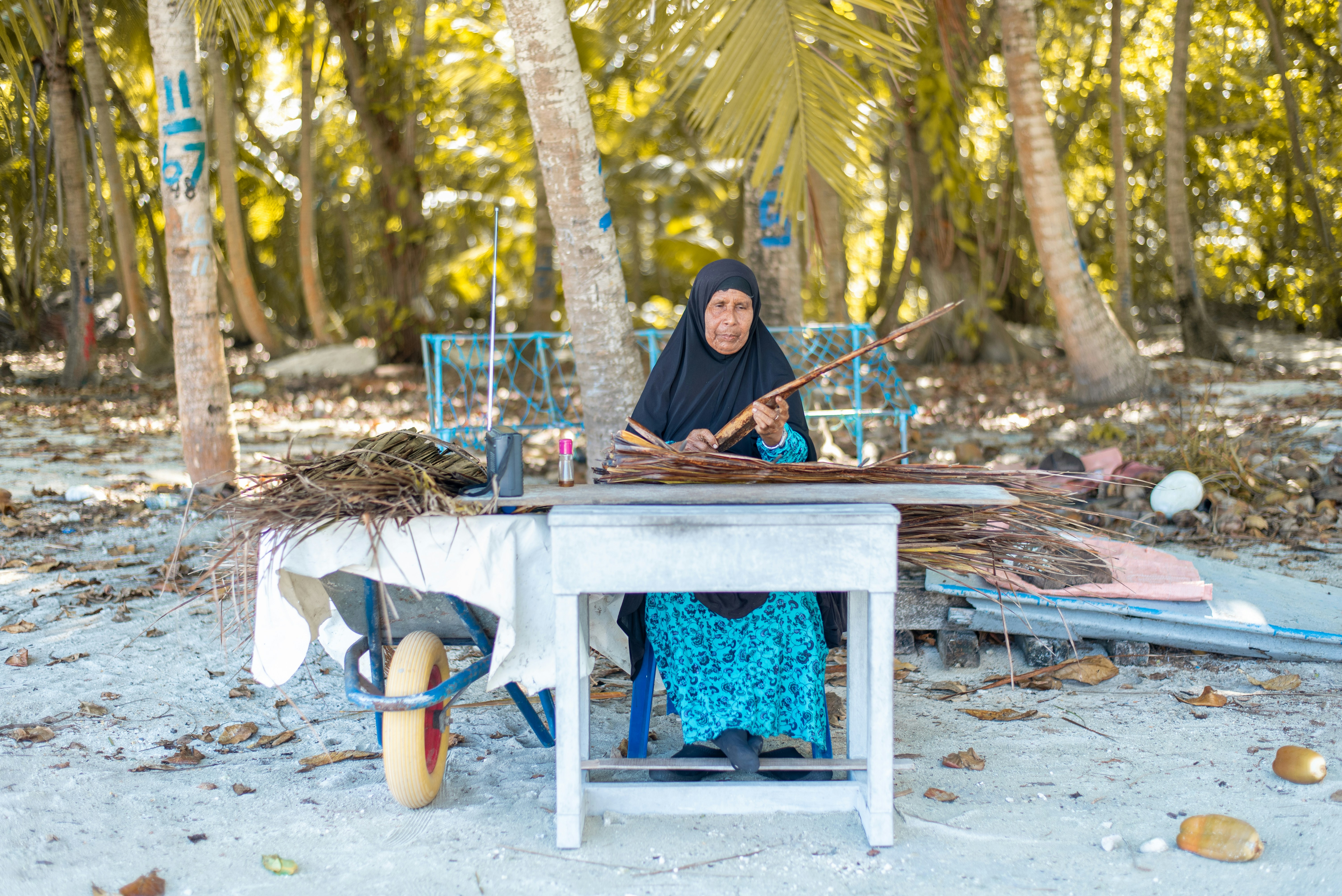 Thatch weaving, locally known as Fangi Vinun is a significant form traditional handicraft of the Maldives. | woman in black hijab sitting on chair