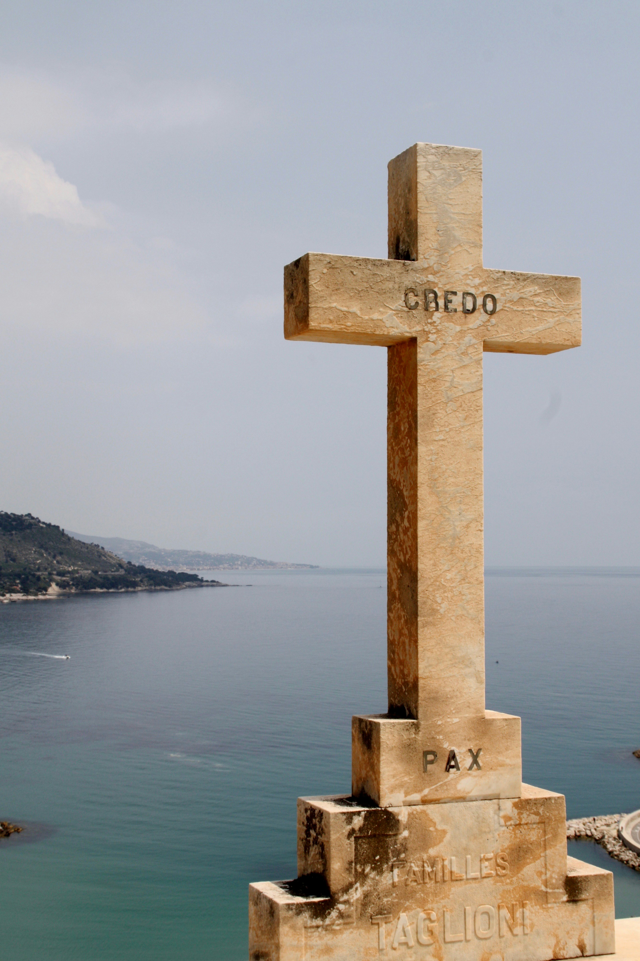 Weathered Cross by the Calm Sea: A Limestone Sentinel Over the Coastline
