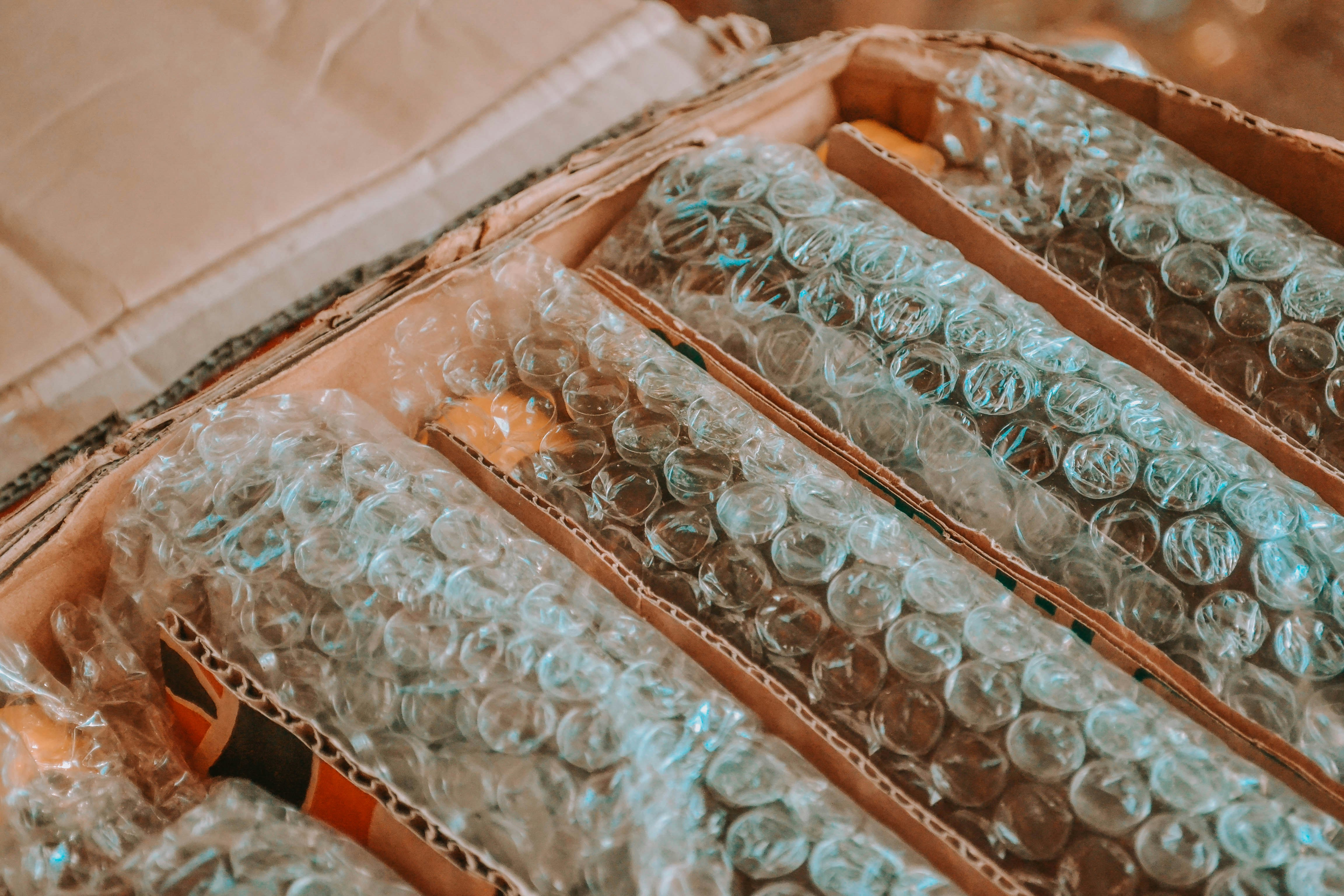 Bottles securely packaged in bubble wrap within a cardboard box, highlighting careful preparation for transport.