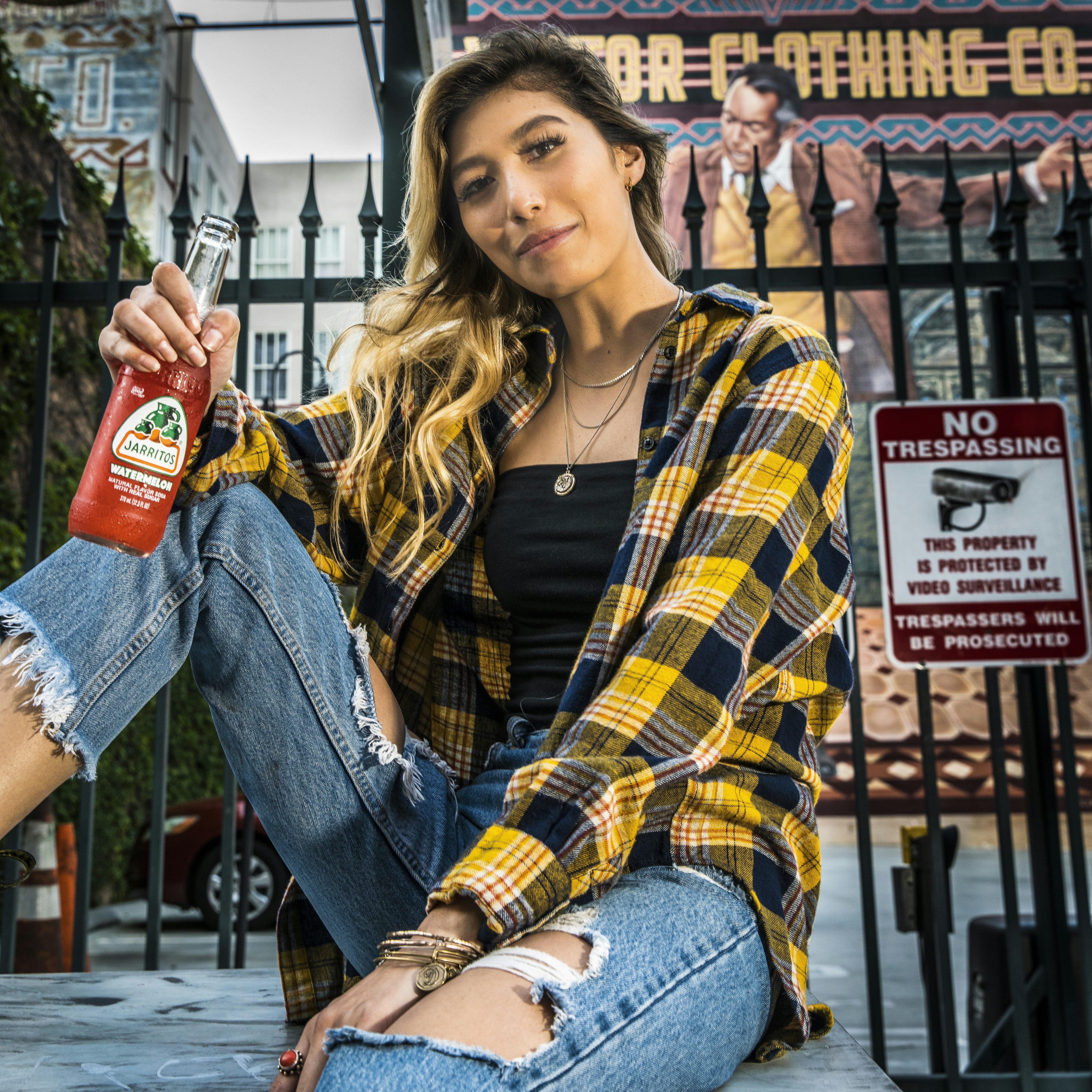 Plaid Confidence by the Gate: An Urban Portrait with a Red Bottle Prop