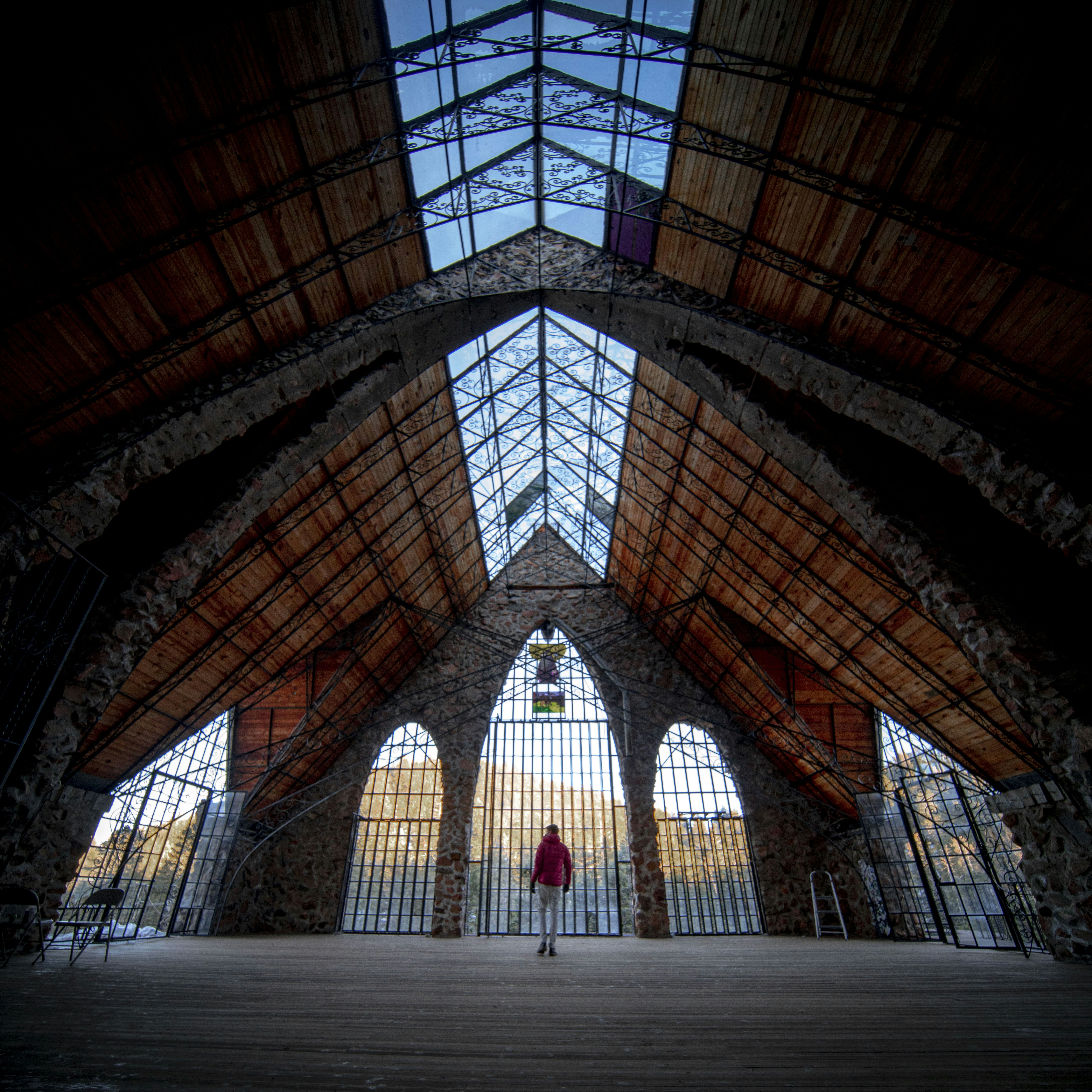 Lines Converge on a Lone Figure in a Glass-Roofed Stone Hall