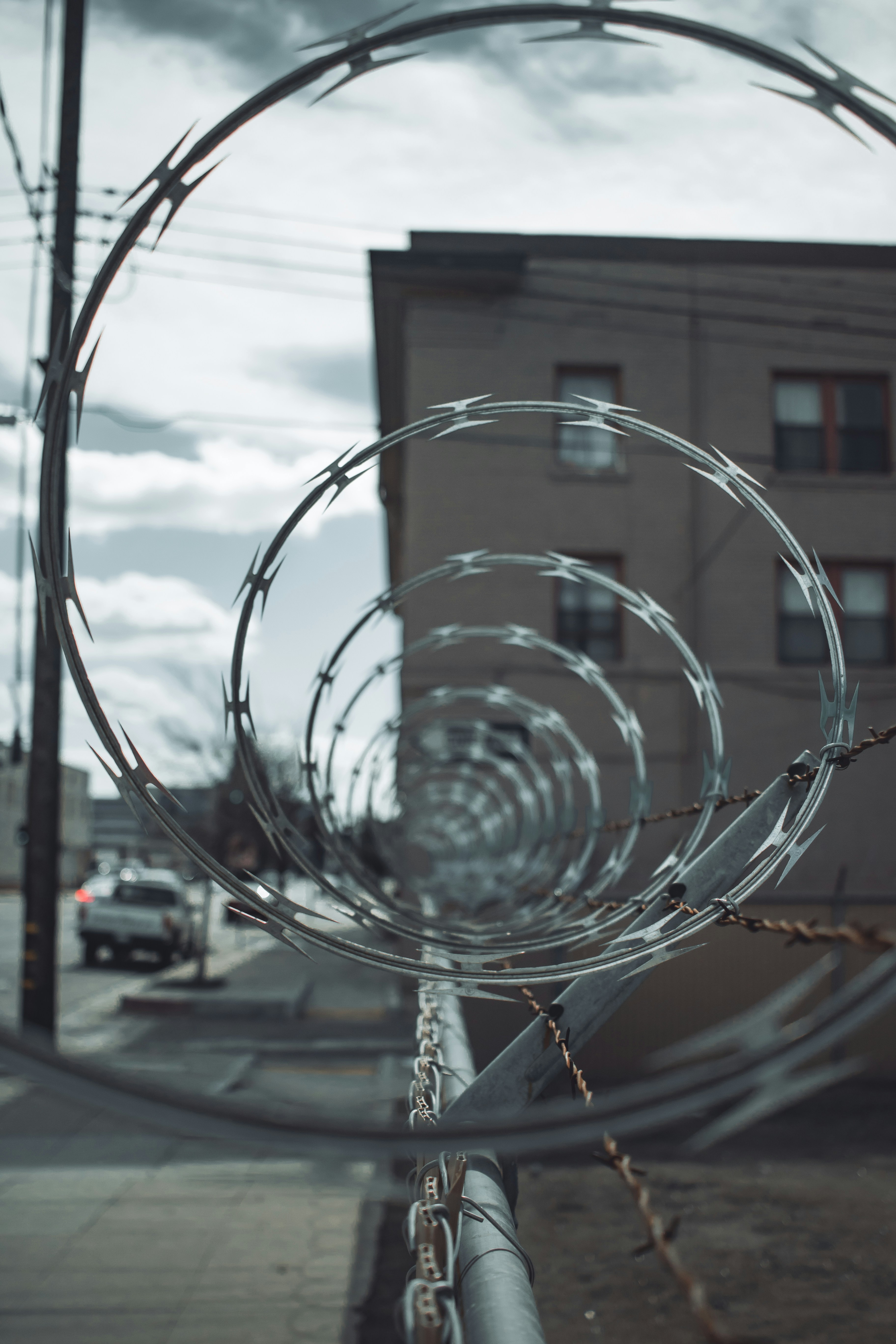 Concentric Barbed-Wire Rings Recede Into an Urban Corridor