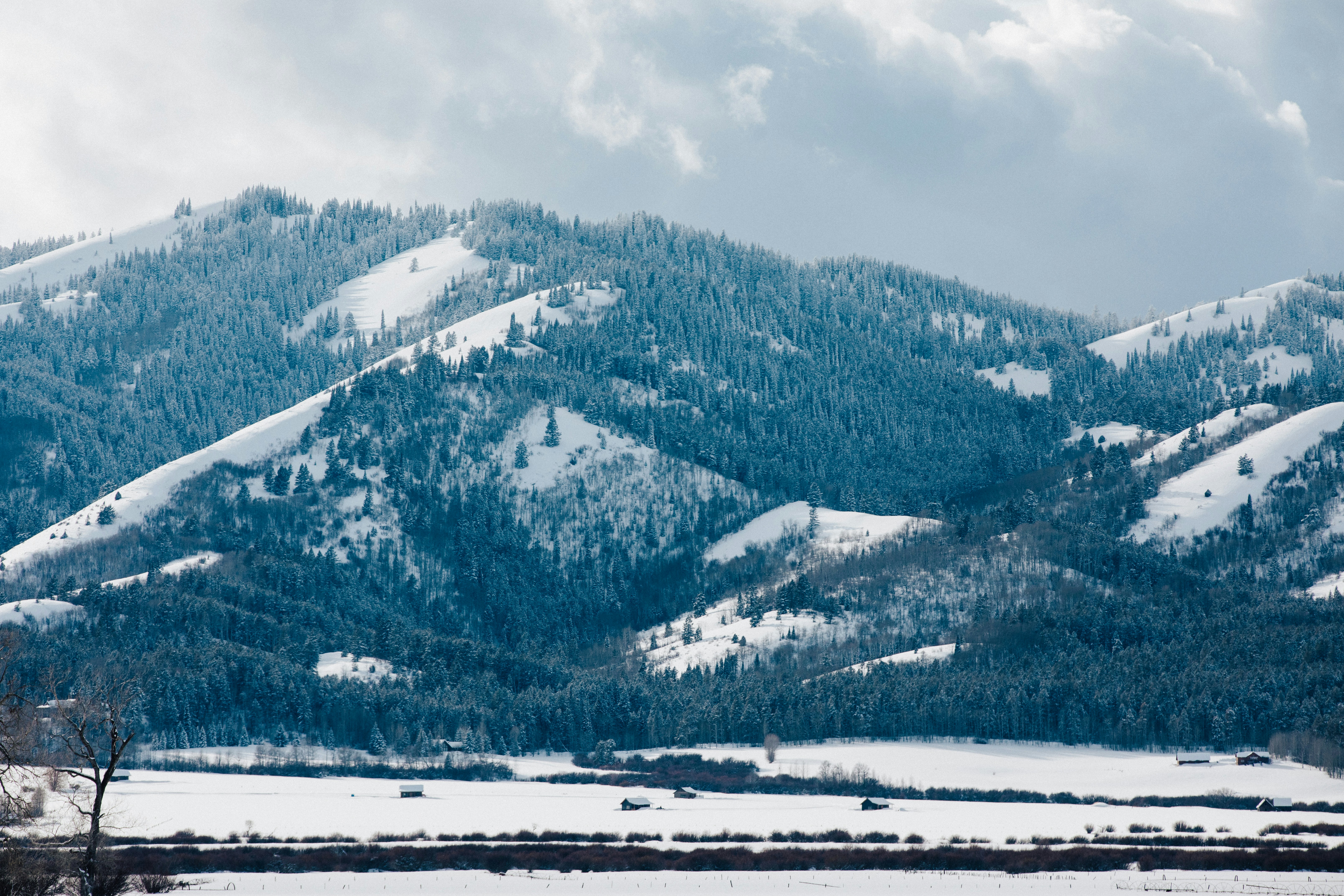 Snow-dusted mountains under a cloudy sky with patches of sunlight.