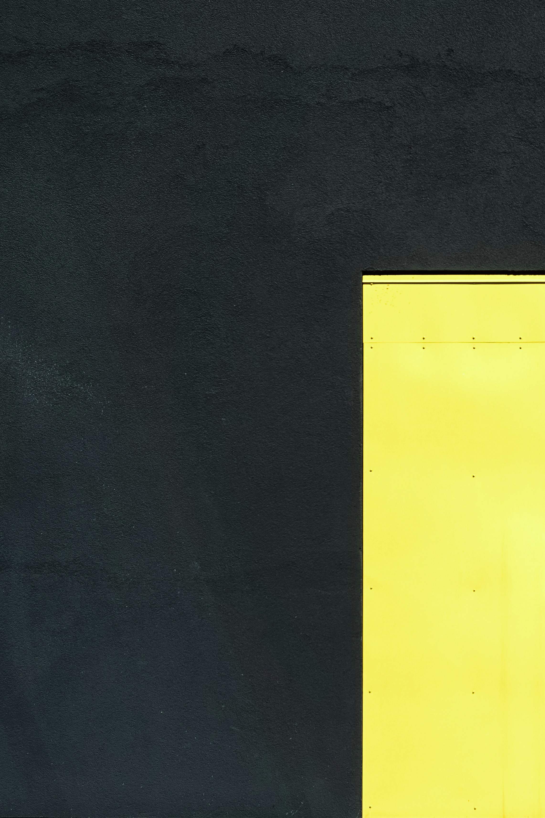 Yellow Door in Black Wall. Abstract Background.
