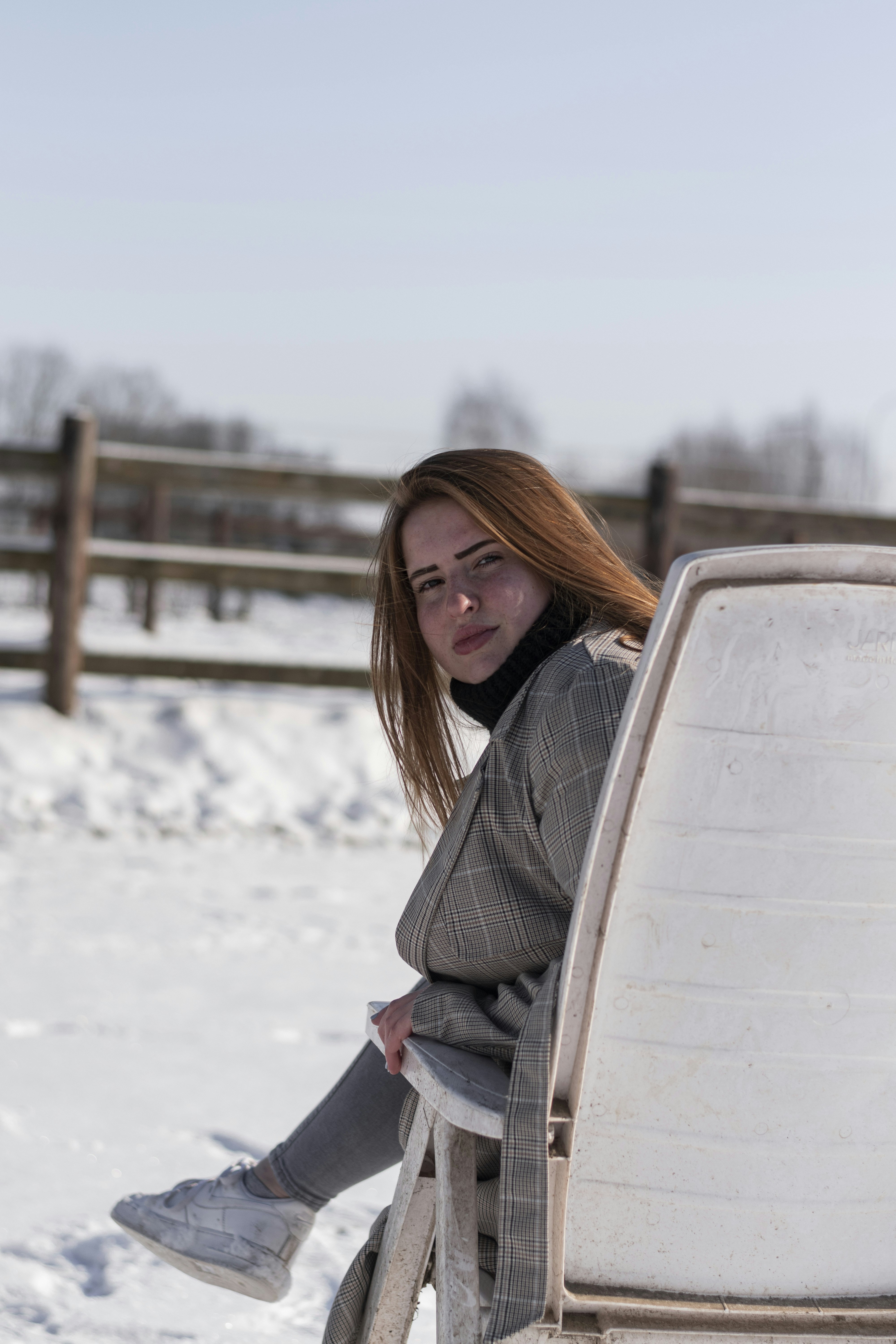 Snowbound Portrait: Red Hair peeks from a chair along a rural fence