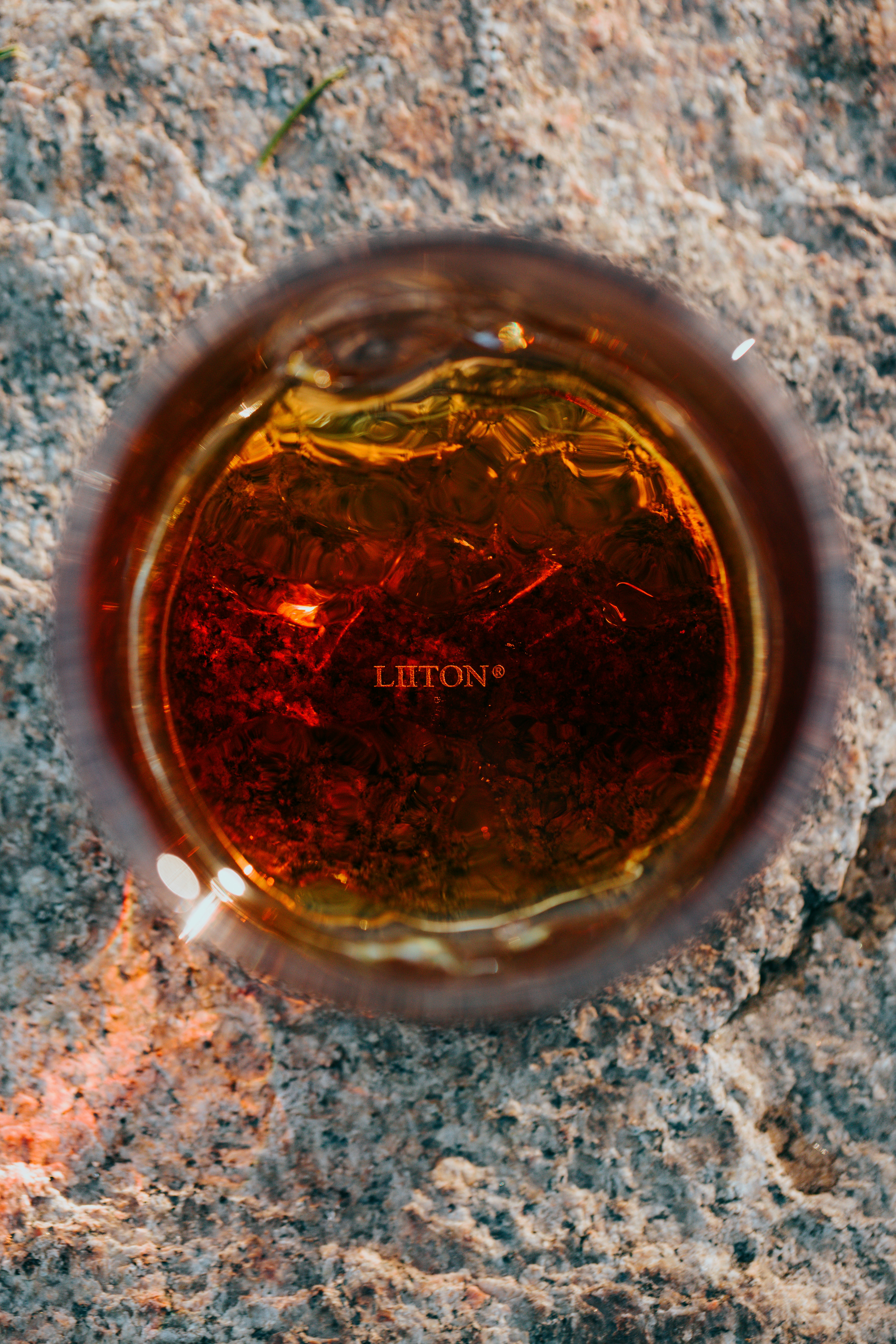 Amber Vessel on Rough Granite: A Top-Down Study of Light and Texture