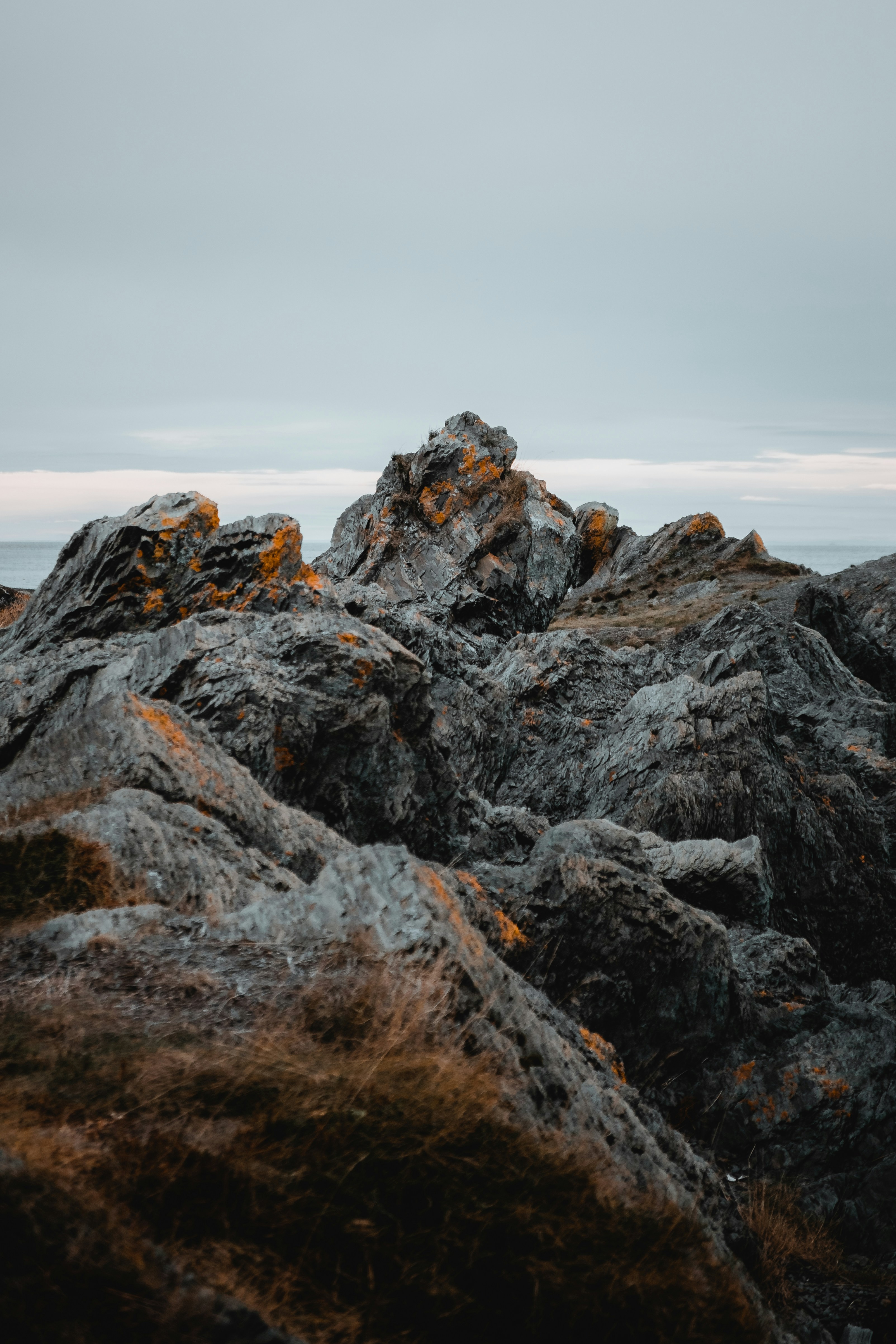 Brown and black rock formation near body of water during daytime photo ...