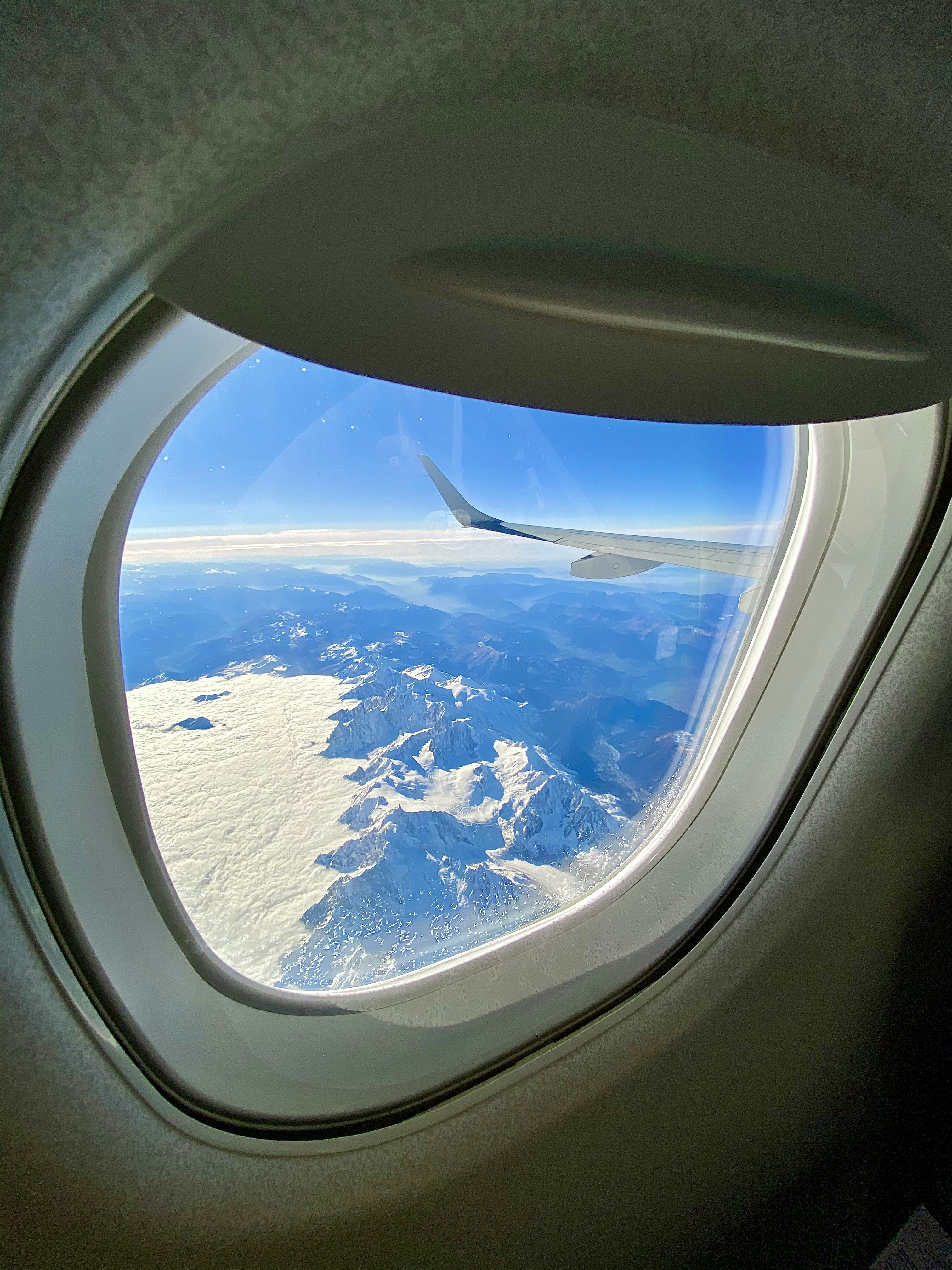 Airplane window view of brown and white mountains during daytime photo ...