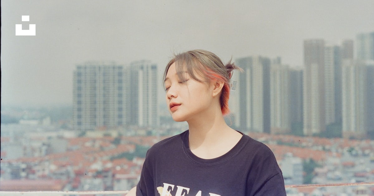 낮 동안 건물 꼭대기에 서 있는 흑백 크루넥 티셔츠를 입은 여자 사진 Unsplash의 무료 하노이 이미지