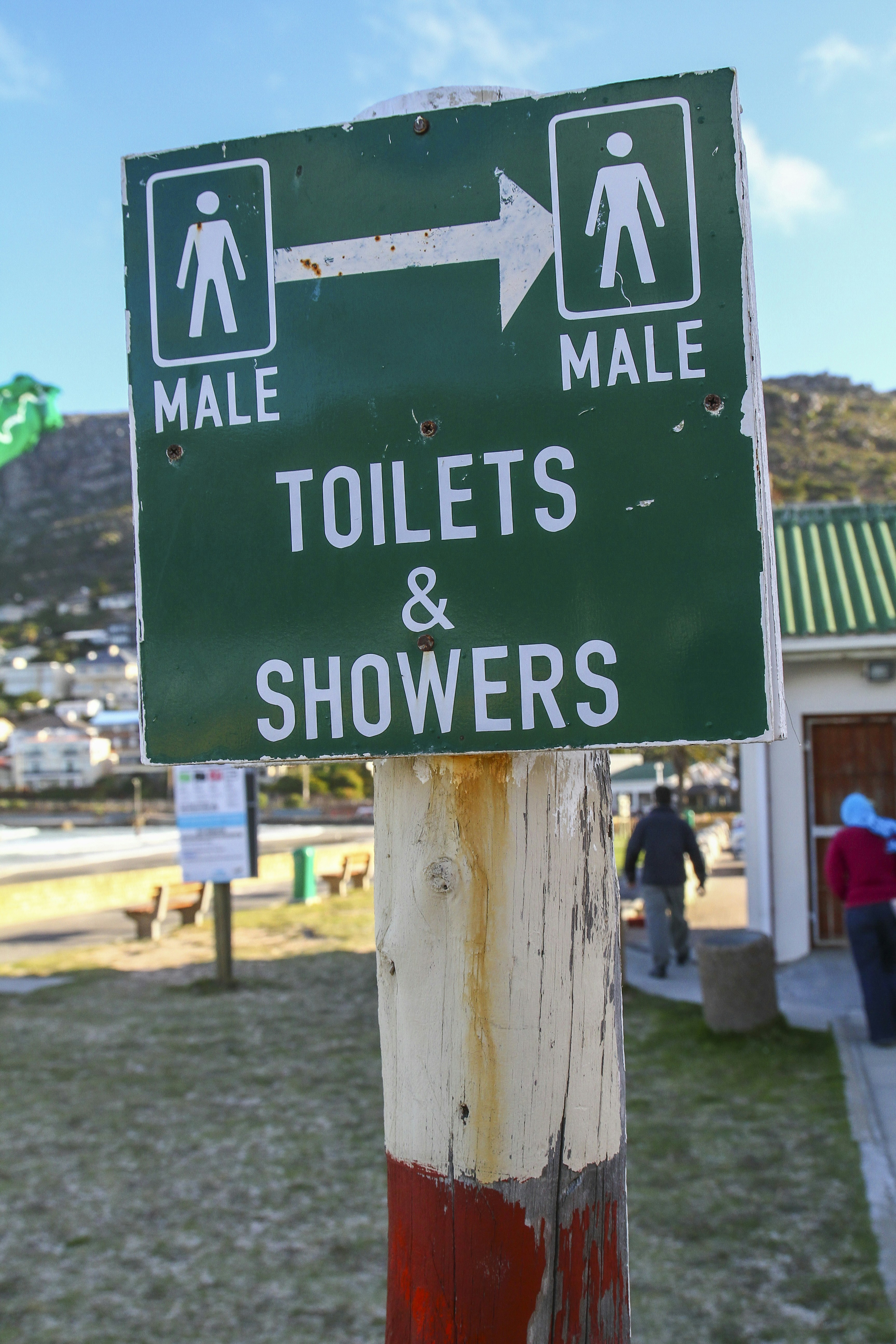 Sign directing men to toilets and showers, featuring clear symbols and text for easy navigation.