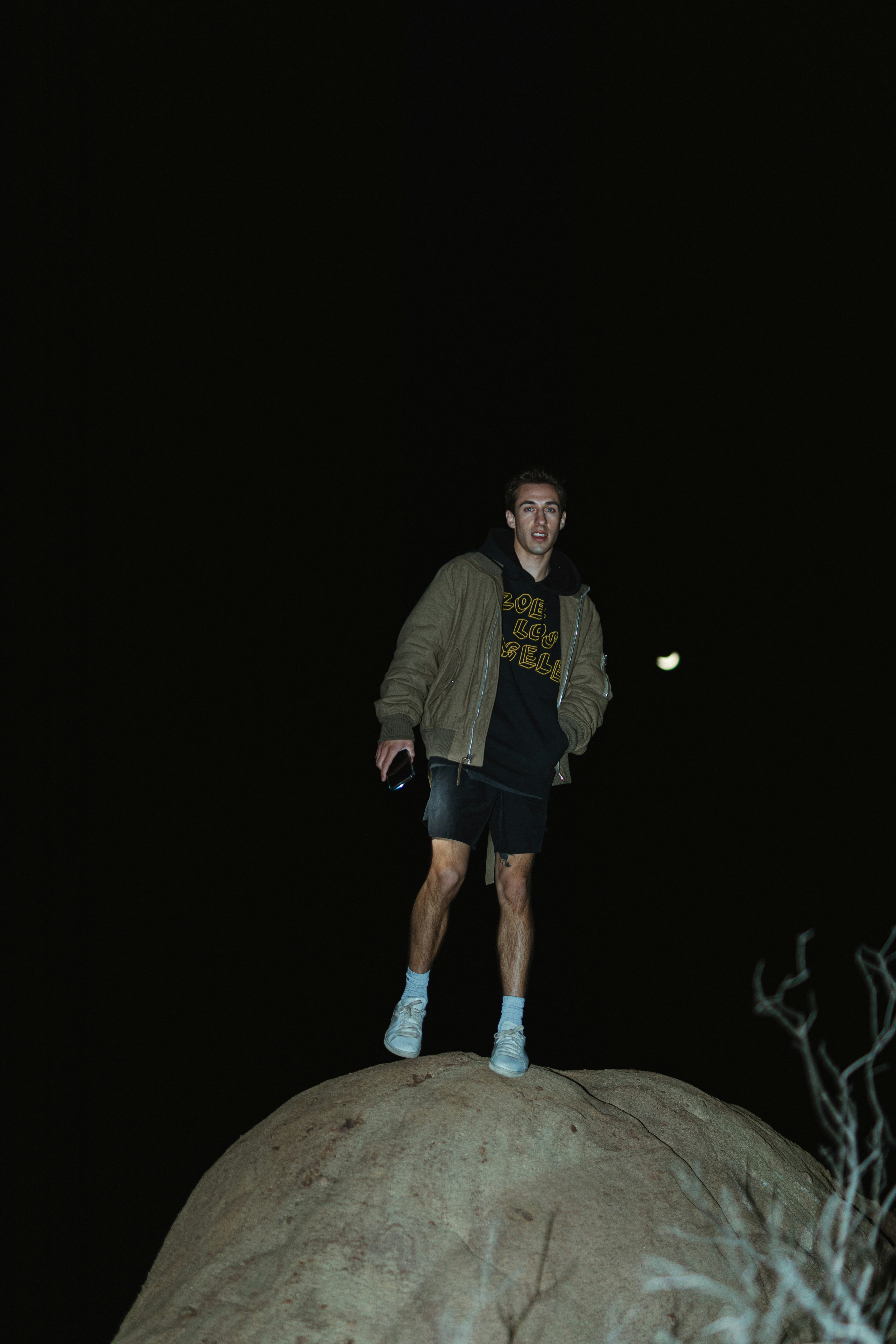 man in black jacket standing on brown rock