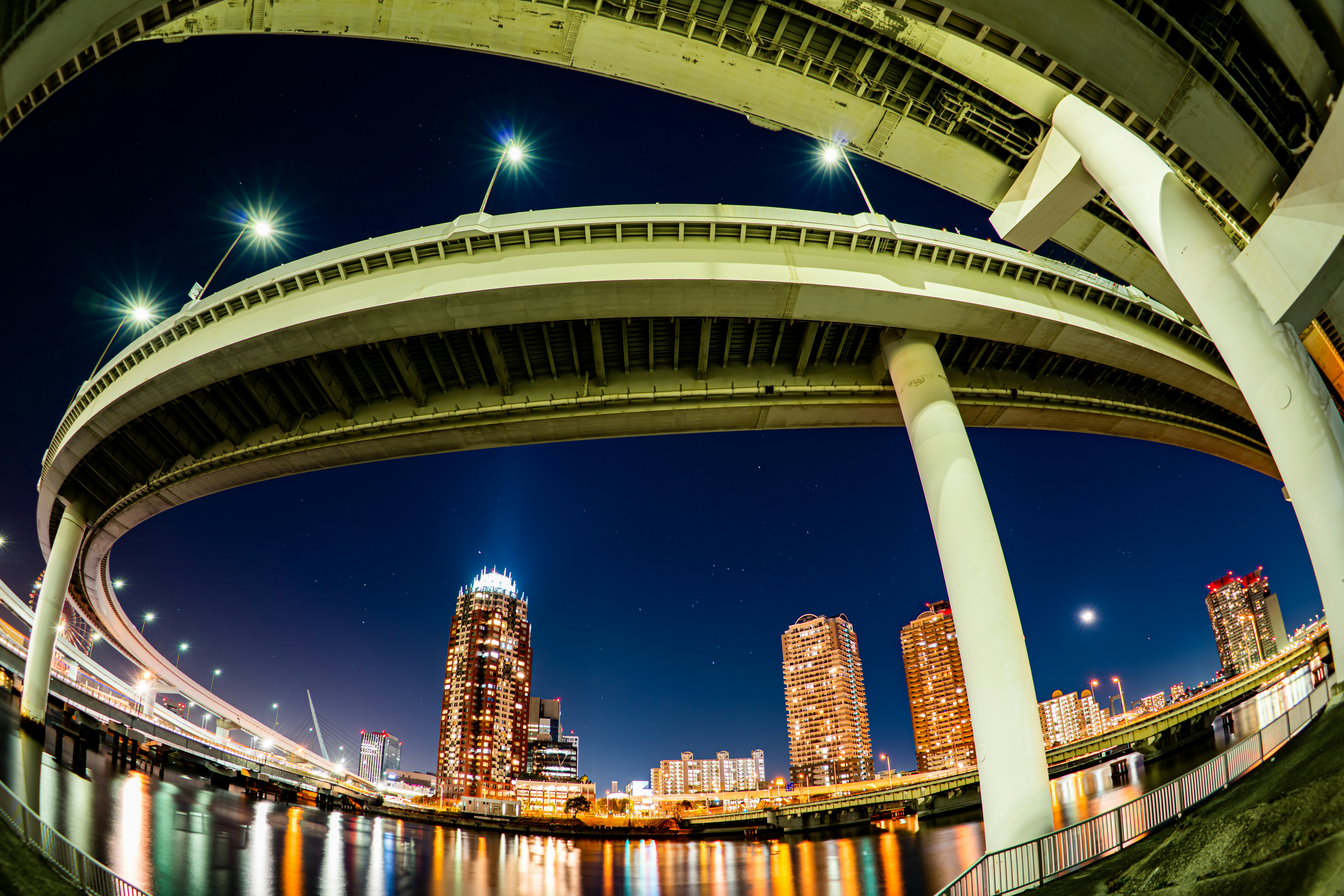 Curved overpass frames a city skyline with illuminated skyscrapers at night.