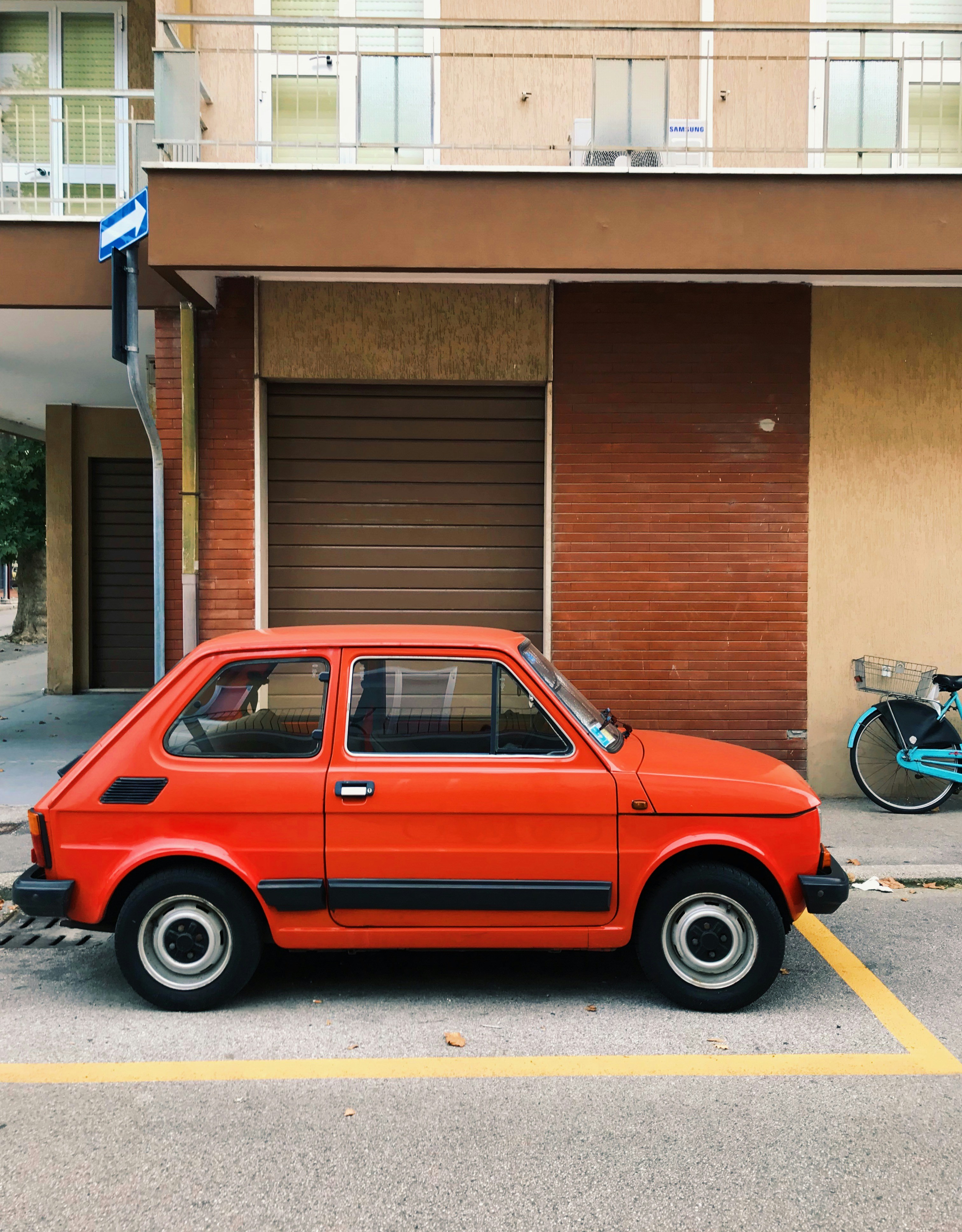 Sunlit Red Microcar Framed by Urban Facades