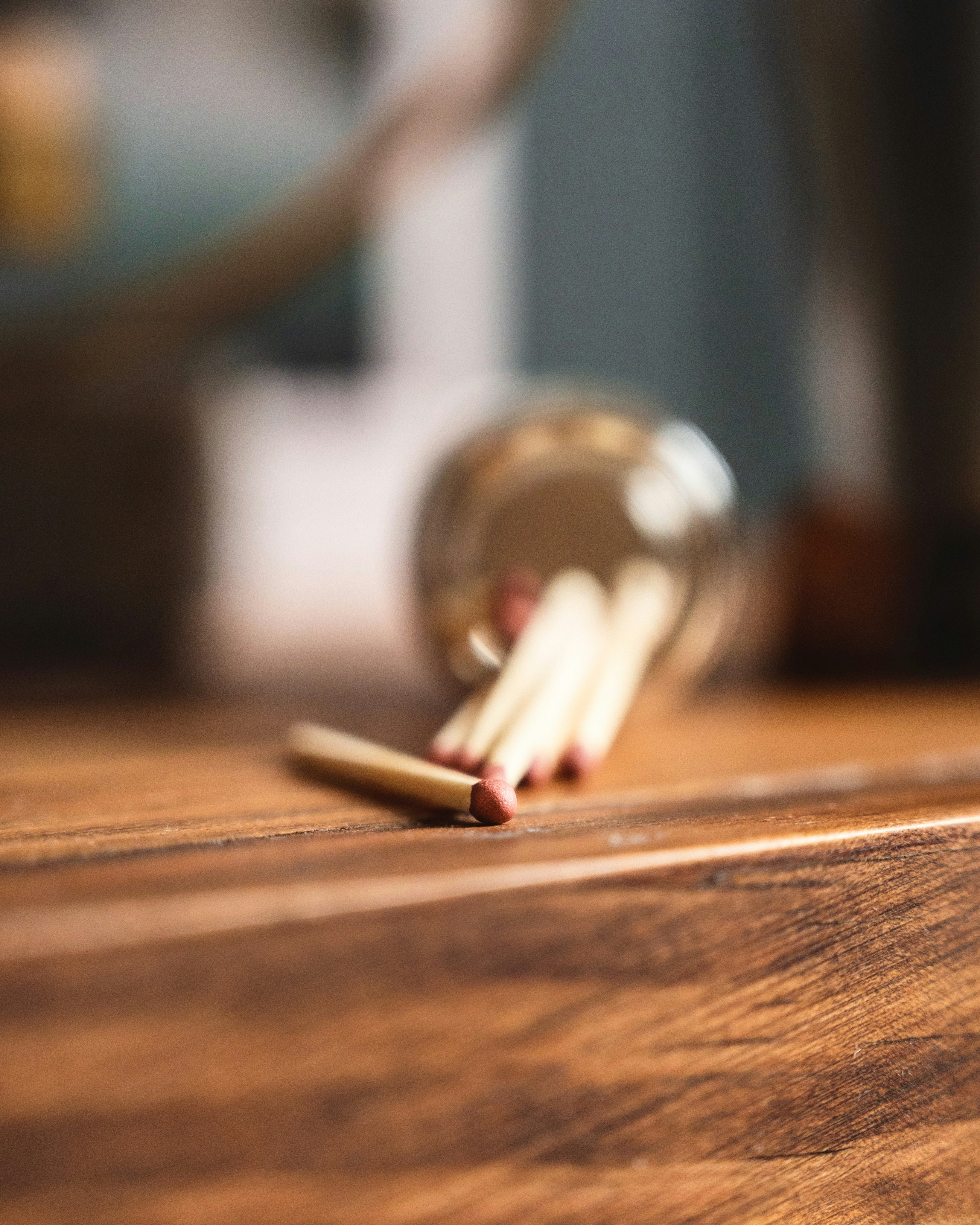 Blurry matchstick on a wooden surface with a glass vial in the background