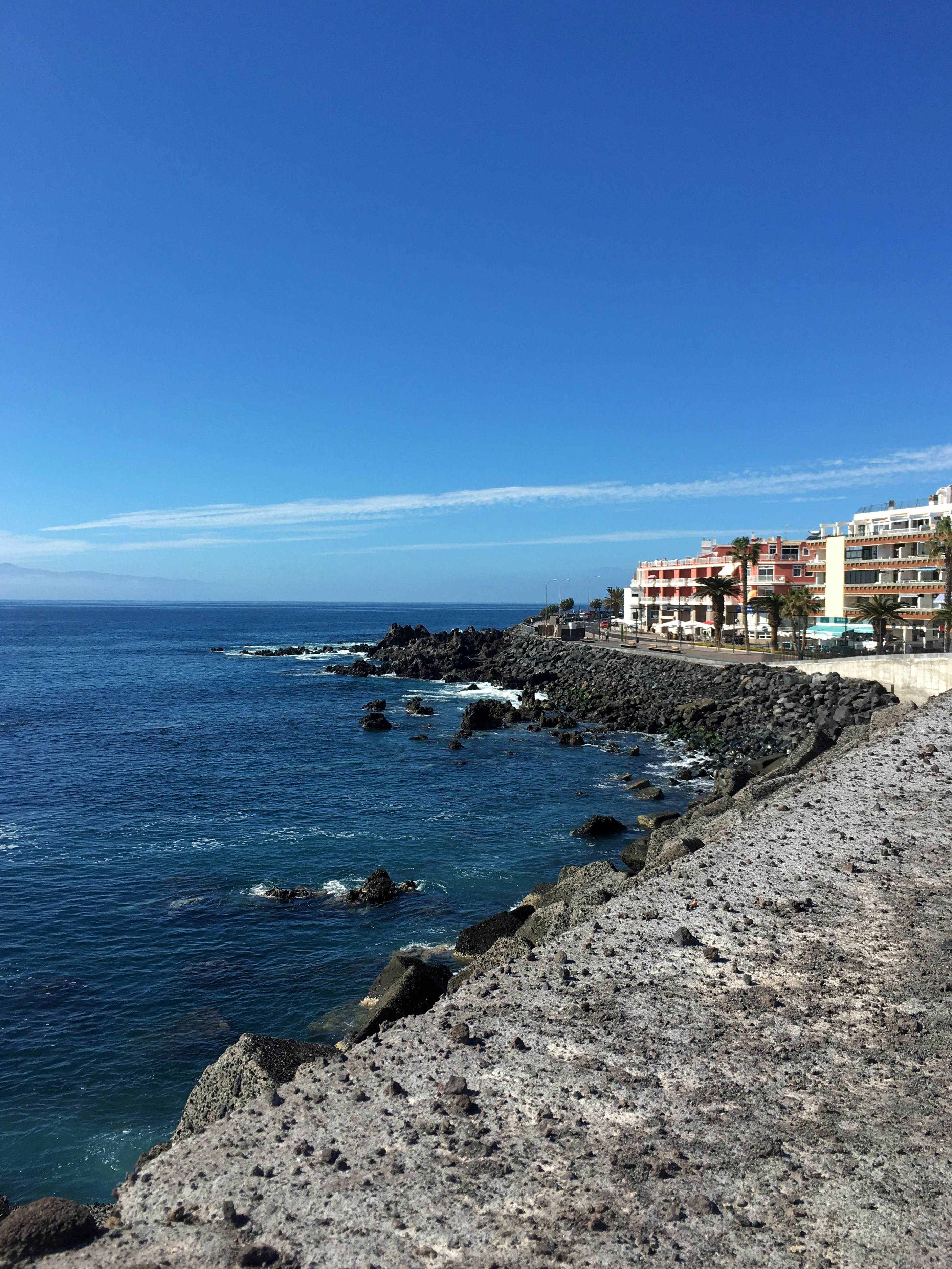 Sunlit Seafront Row: Pastel Buildings at the Edge of a Rocky Breakwater