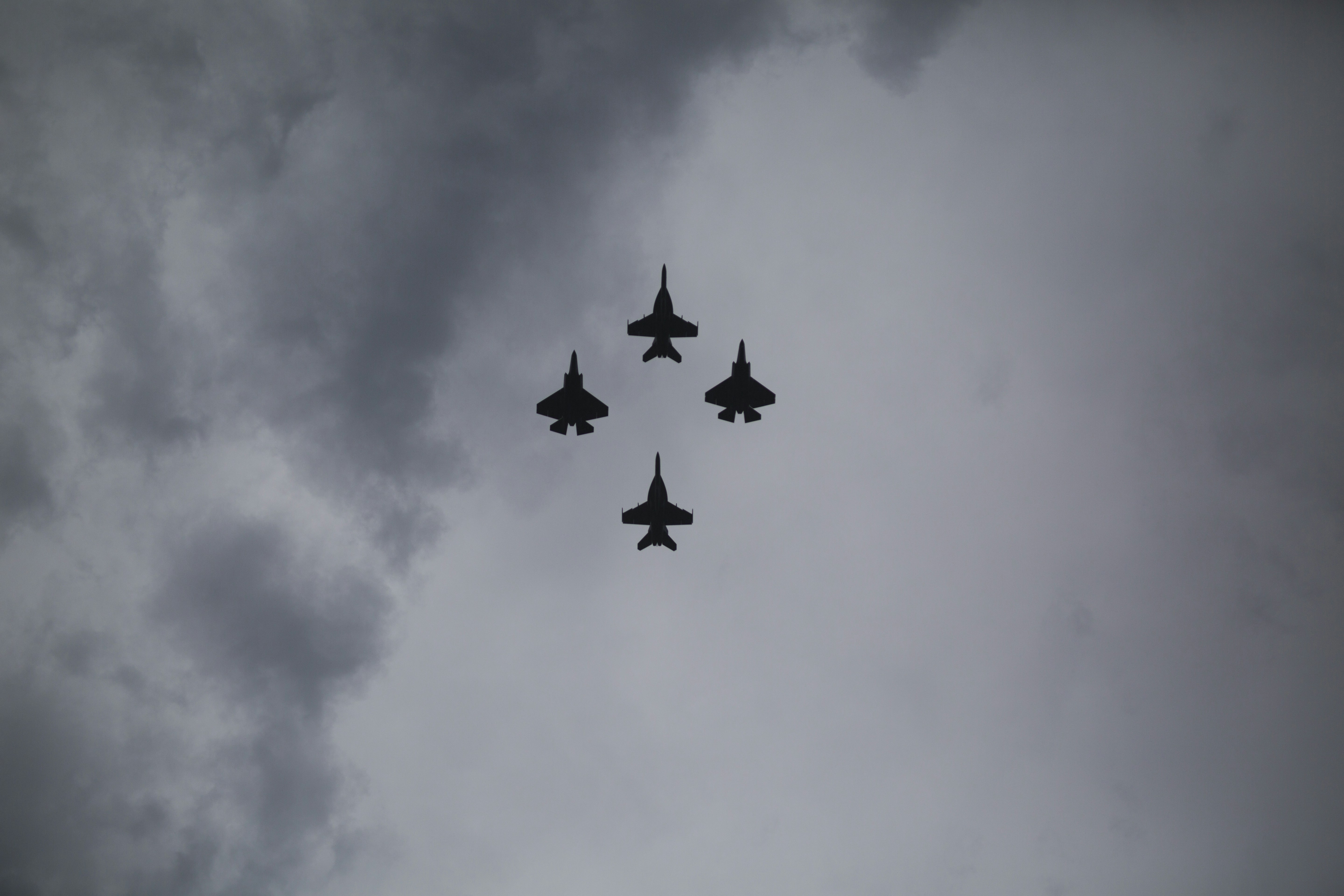Four fighter jets in a precise aerial formation against a dramatic cloudy backdrop.