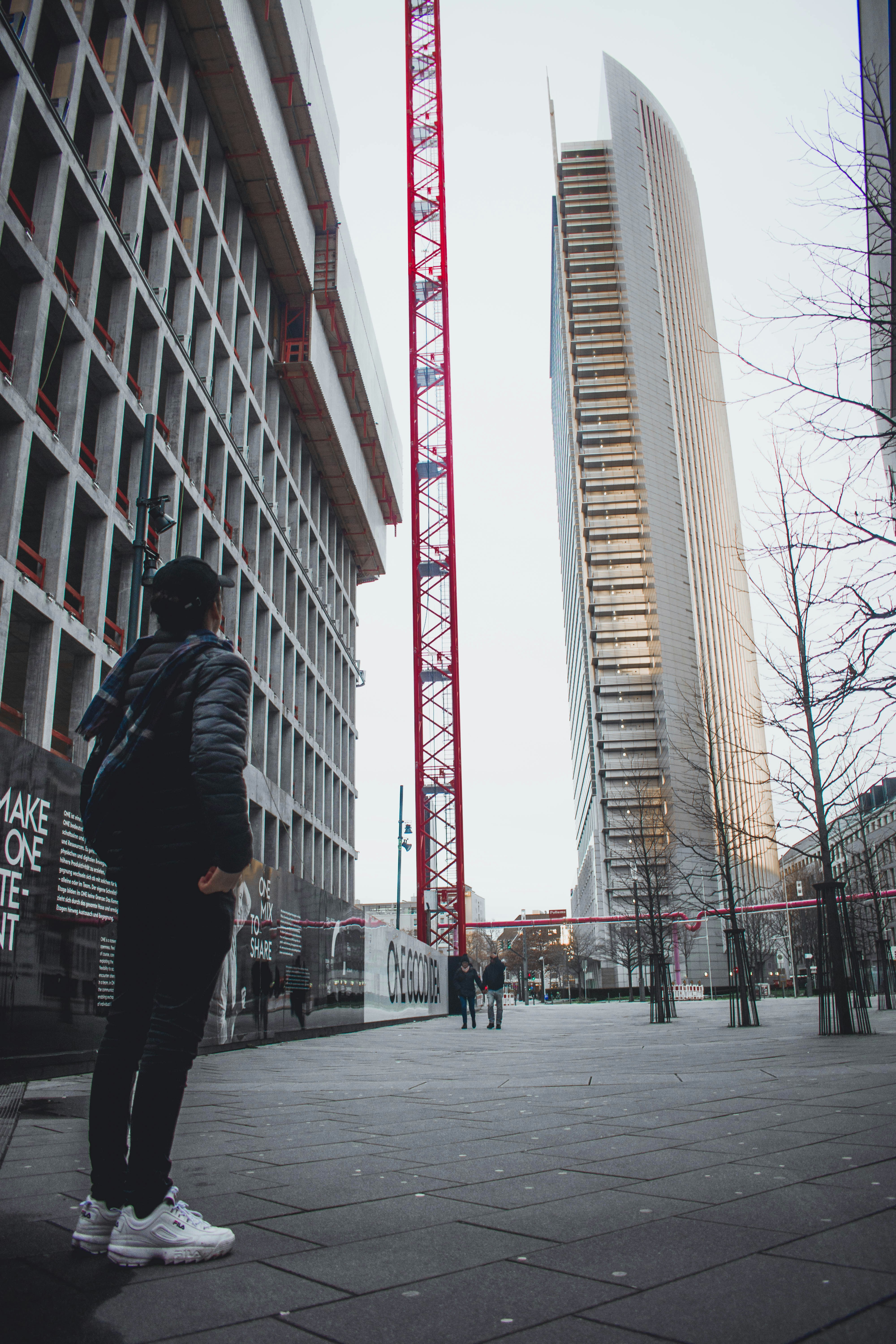 Lone pedestrian confronts a rising urban canyon of steel and glass