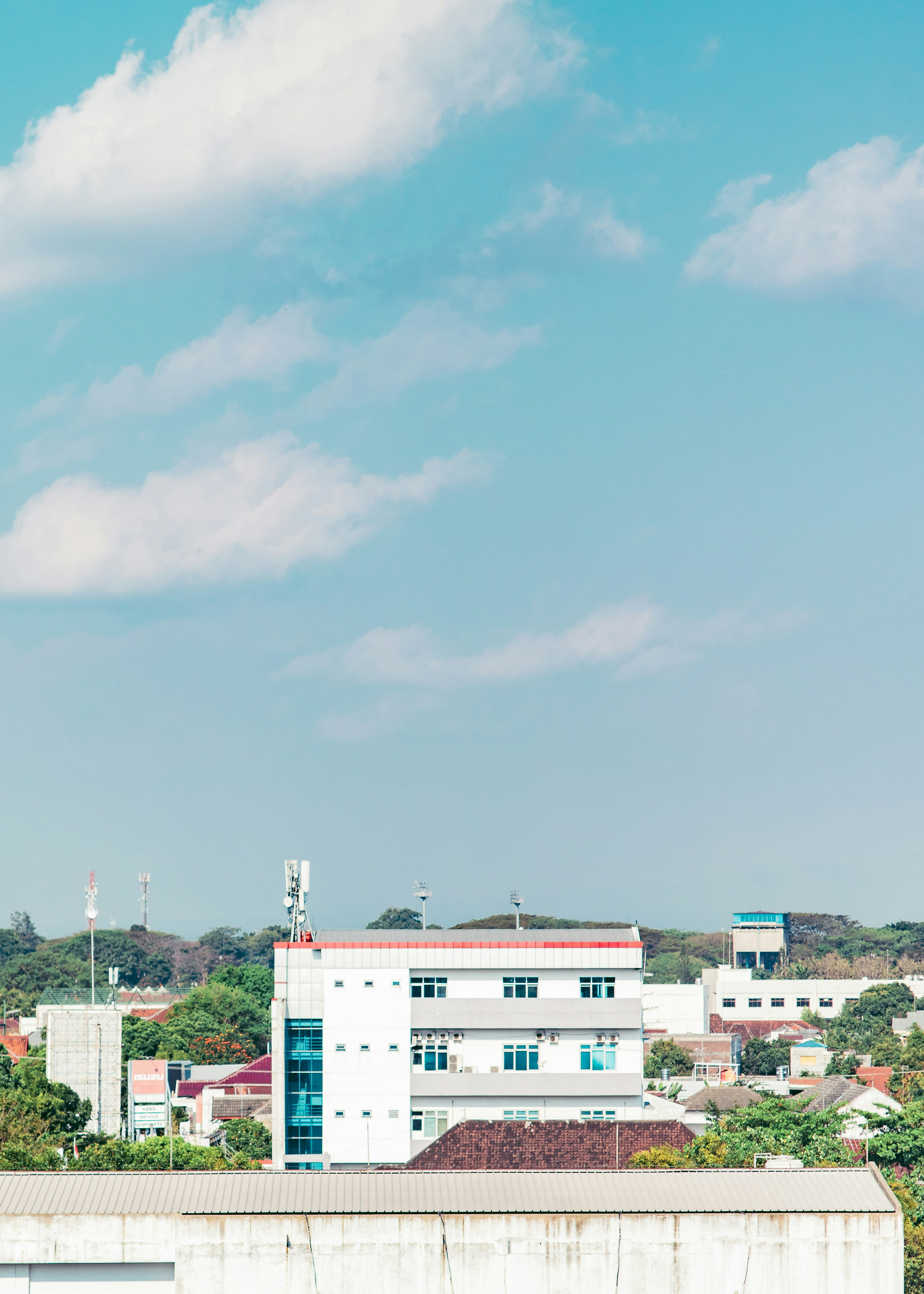 Cityscape with buildings beneath a vibrant blue sky with scattered clouds.