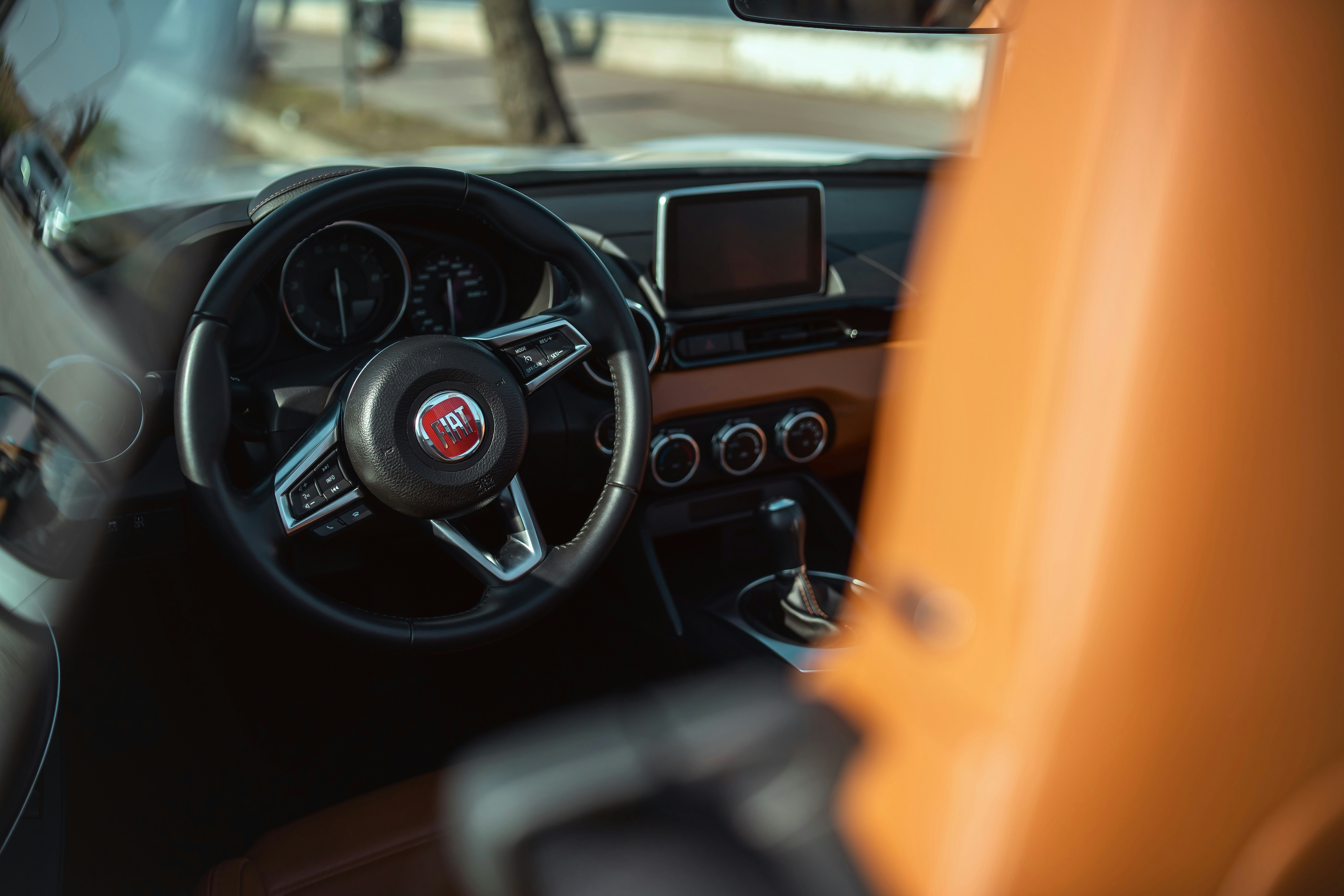 Fiat Core: Close-Up of a Leather-Wrapped Wheel Framed by the Orange Cabin