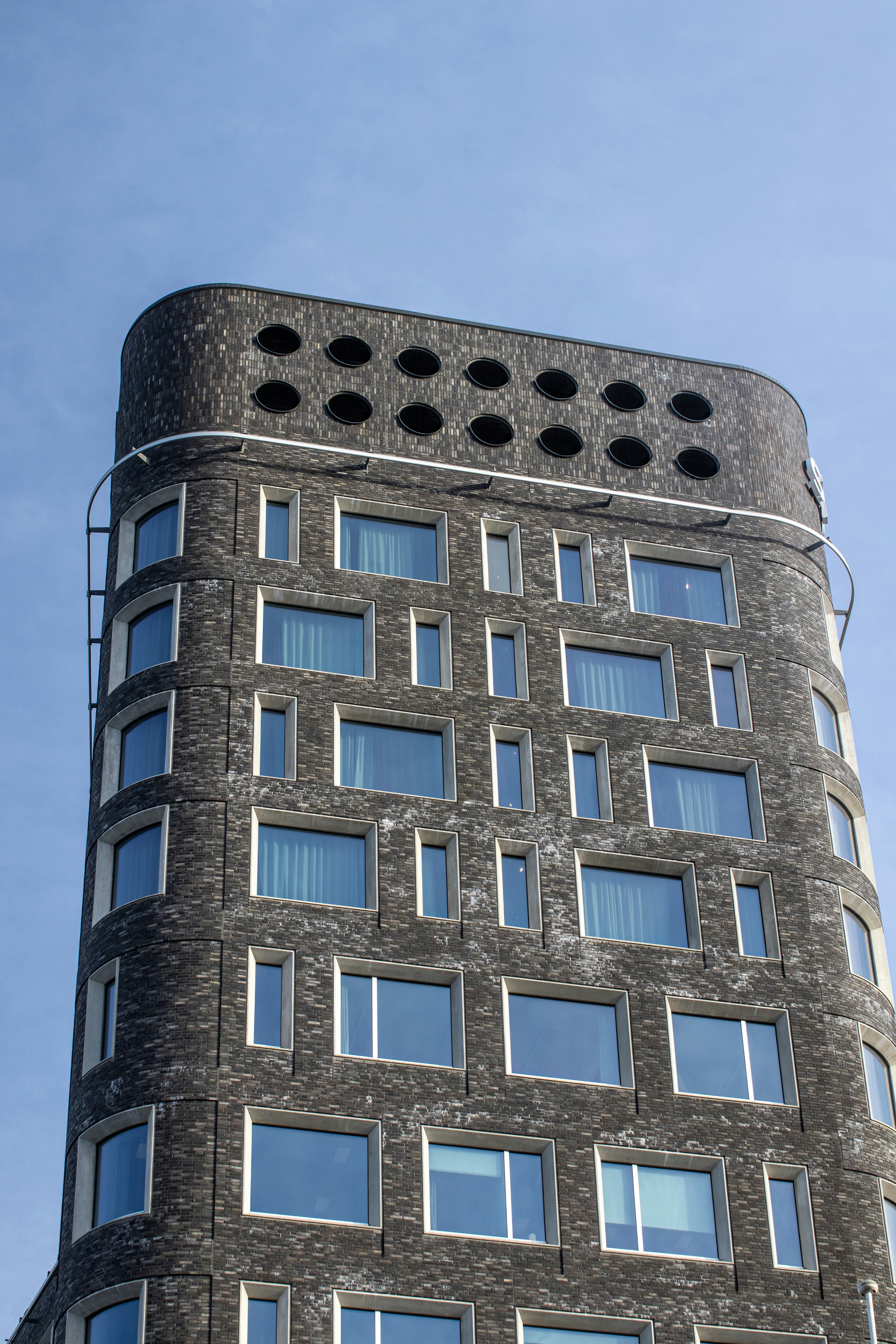 Curved Brick Facade Reaches Toward a Clear Sky