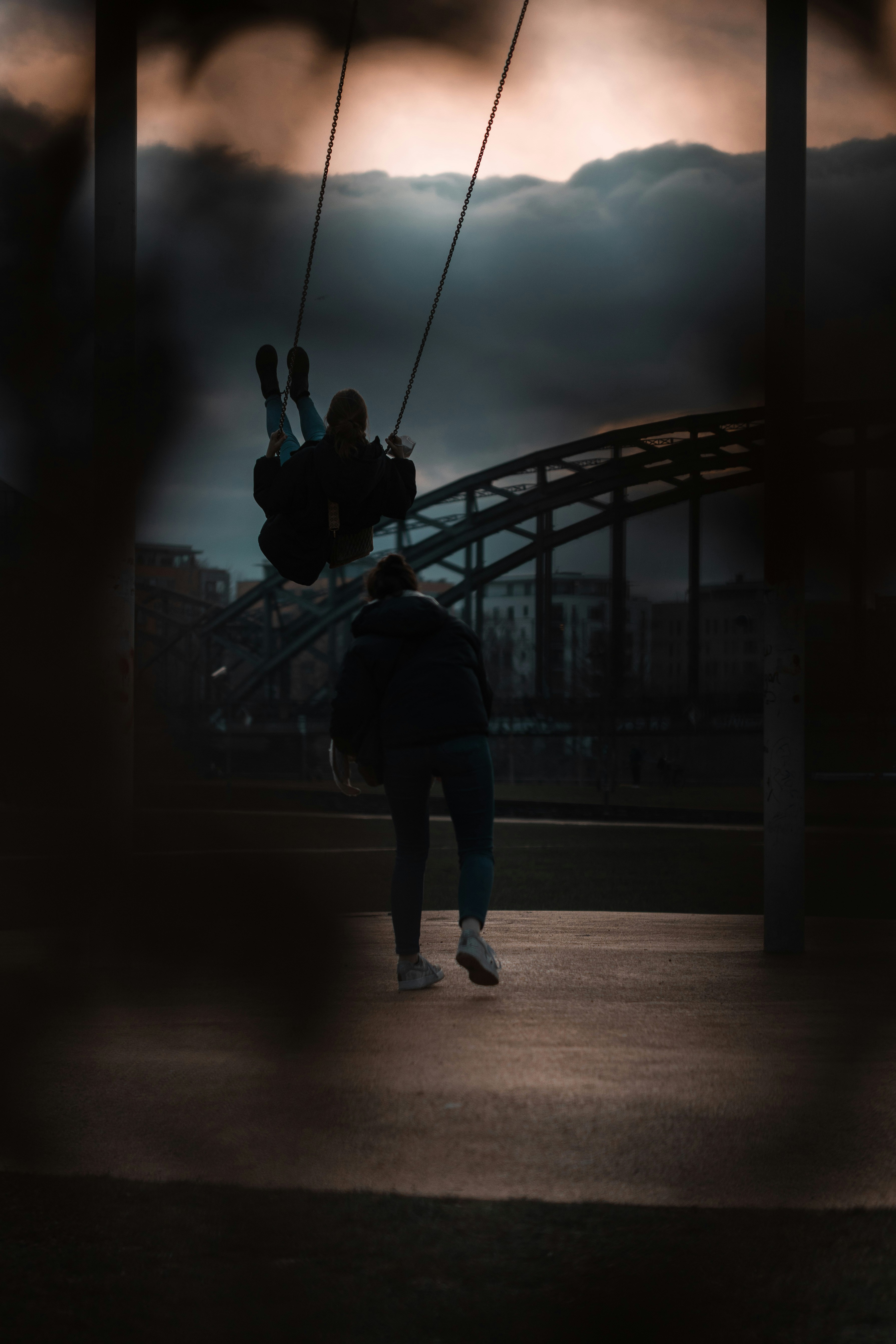 Twilight Swing: Silhouettes Beneath an Industrial Arc
