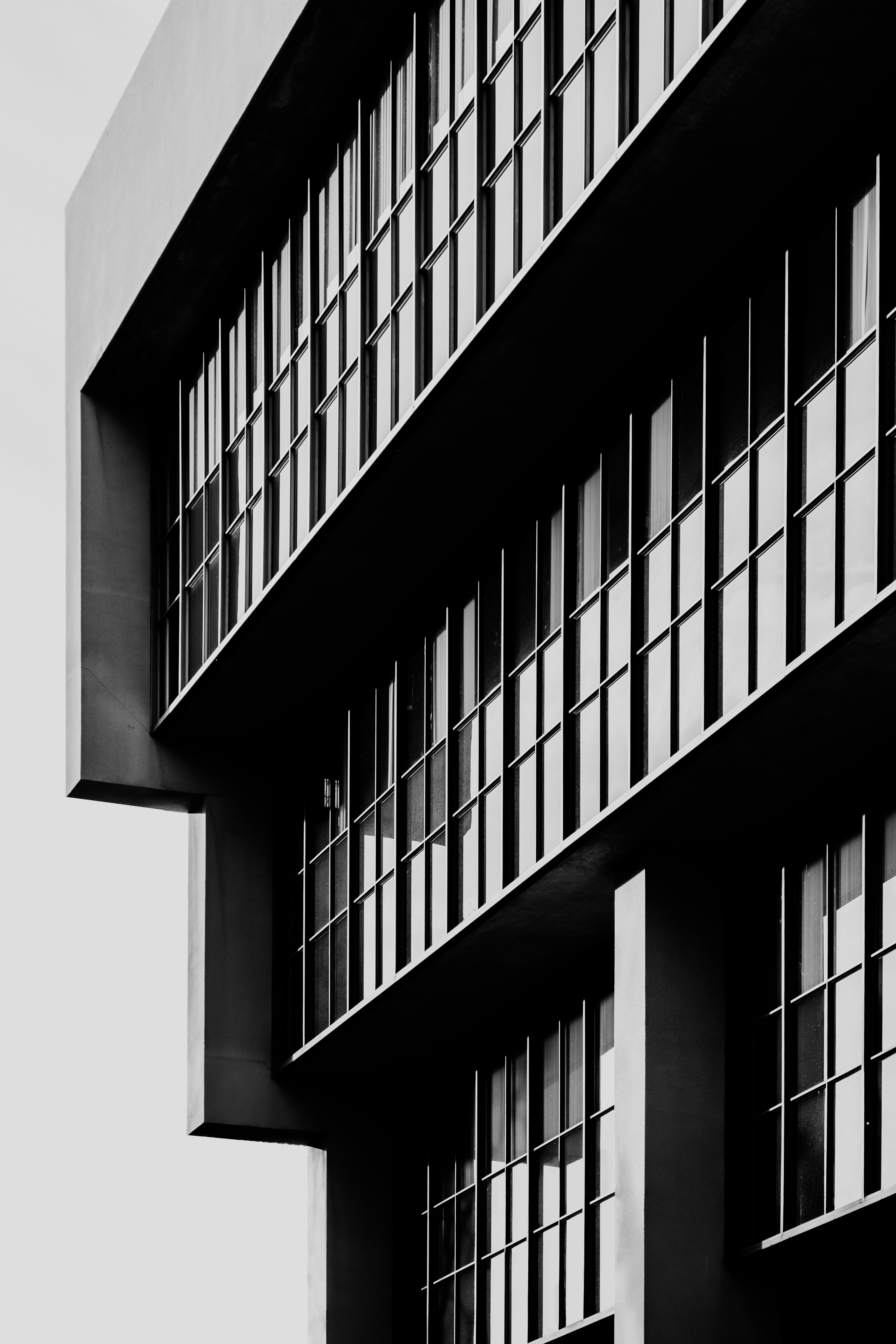Abstract view of modern building facade featuring geometric lines and window patterns in black and white.