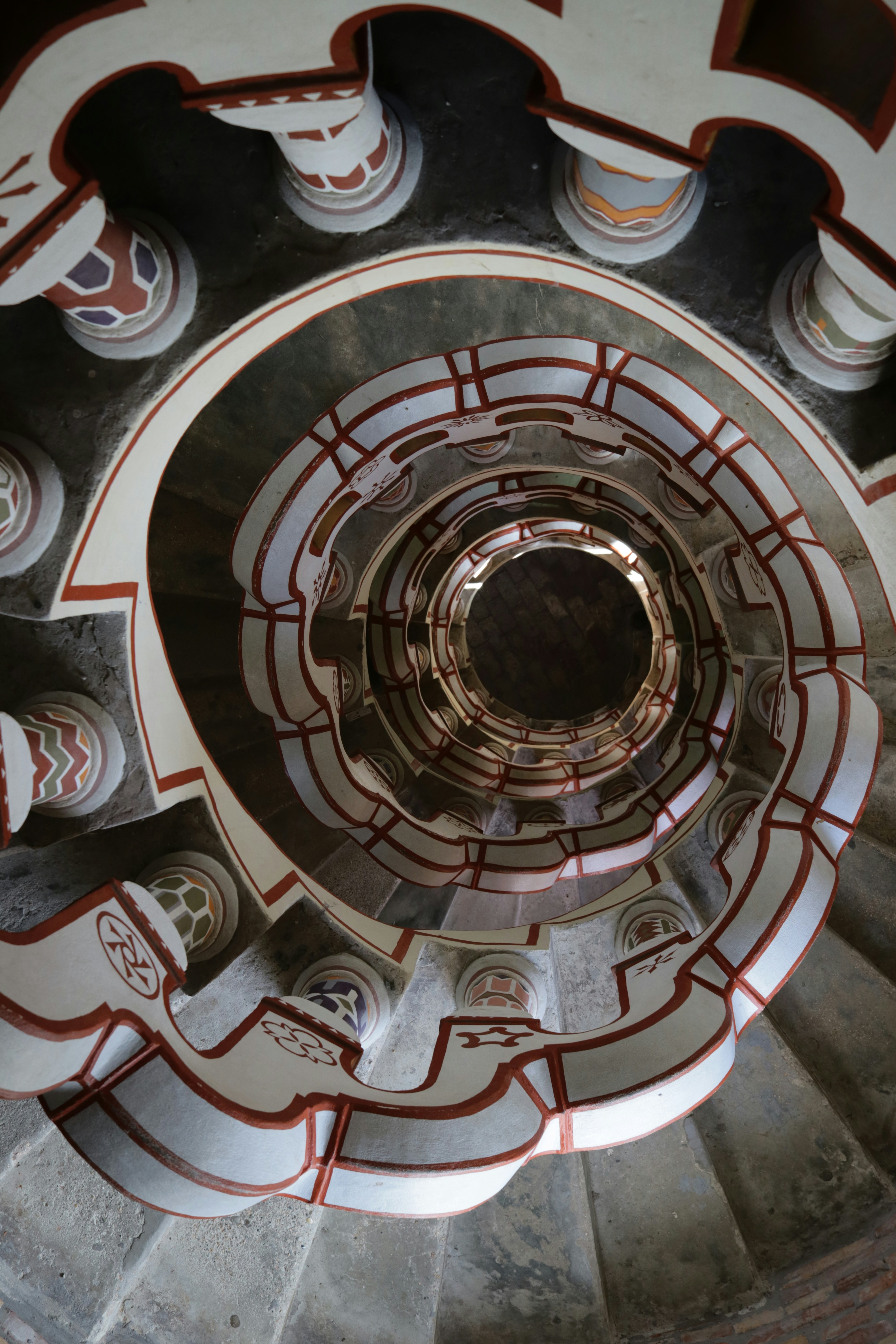 Spiral staircase with intricate patterns and painted pillars in a historical castle.
