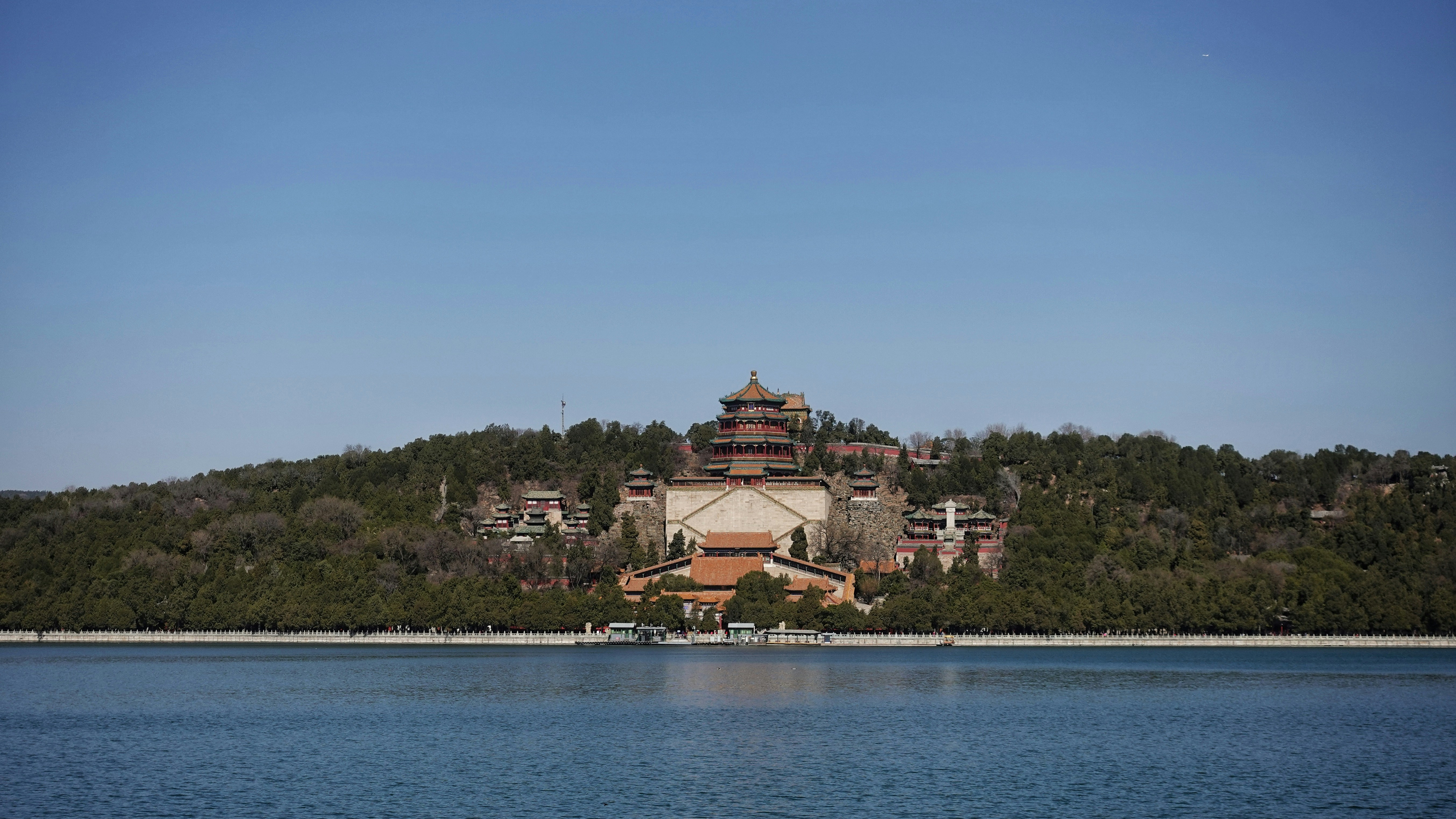 The Summer Palace complex with its ornate architecture sits atop a lush hillside overlooking the serene waters of Kunming Lake.