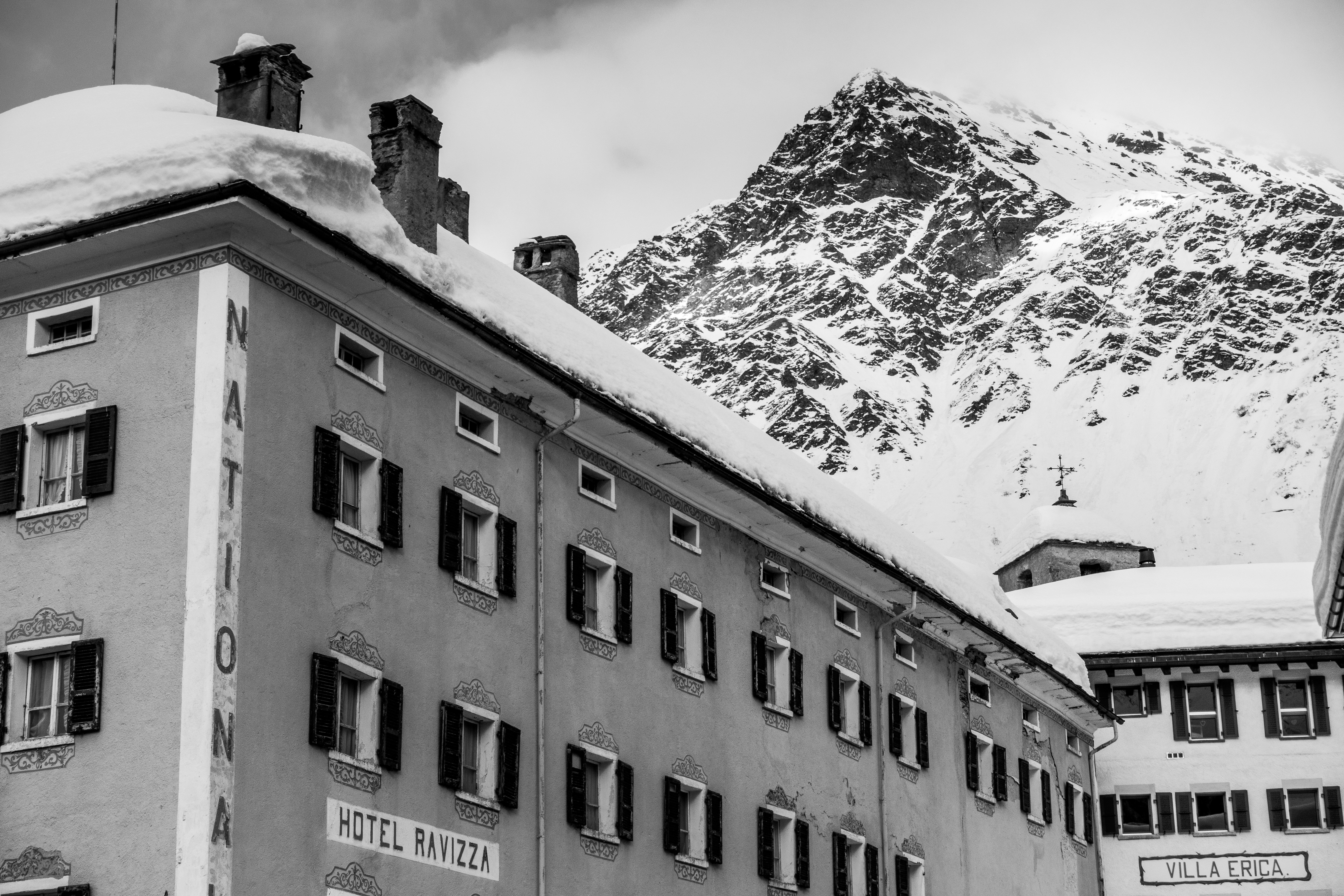 Old hotels in San Bernardino, Switzerland. | grayscale photo of concrete building near mountain range