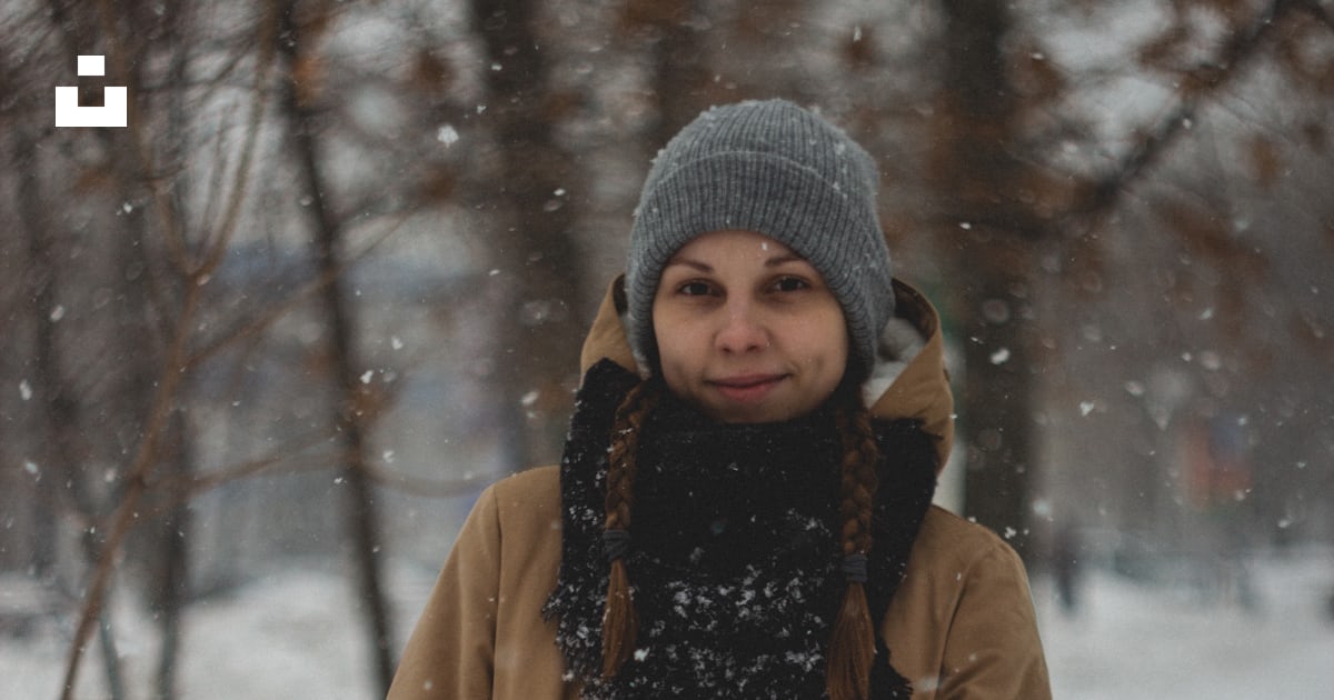 昼間、雪に覆われた地面に立つ茶色のコートを着た女性の写真 Unsplashの肖像の無料画像