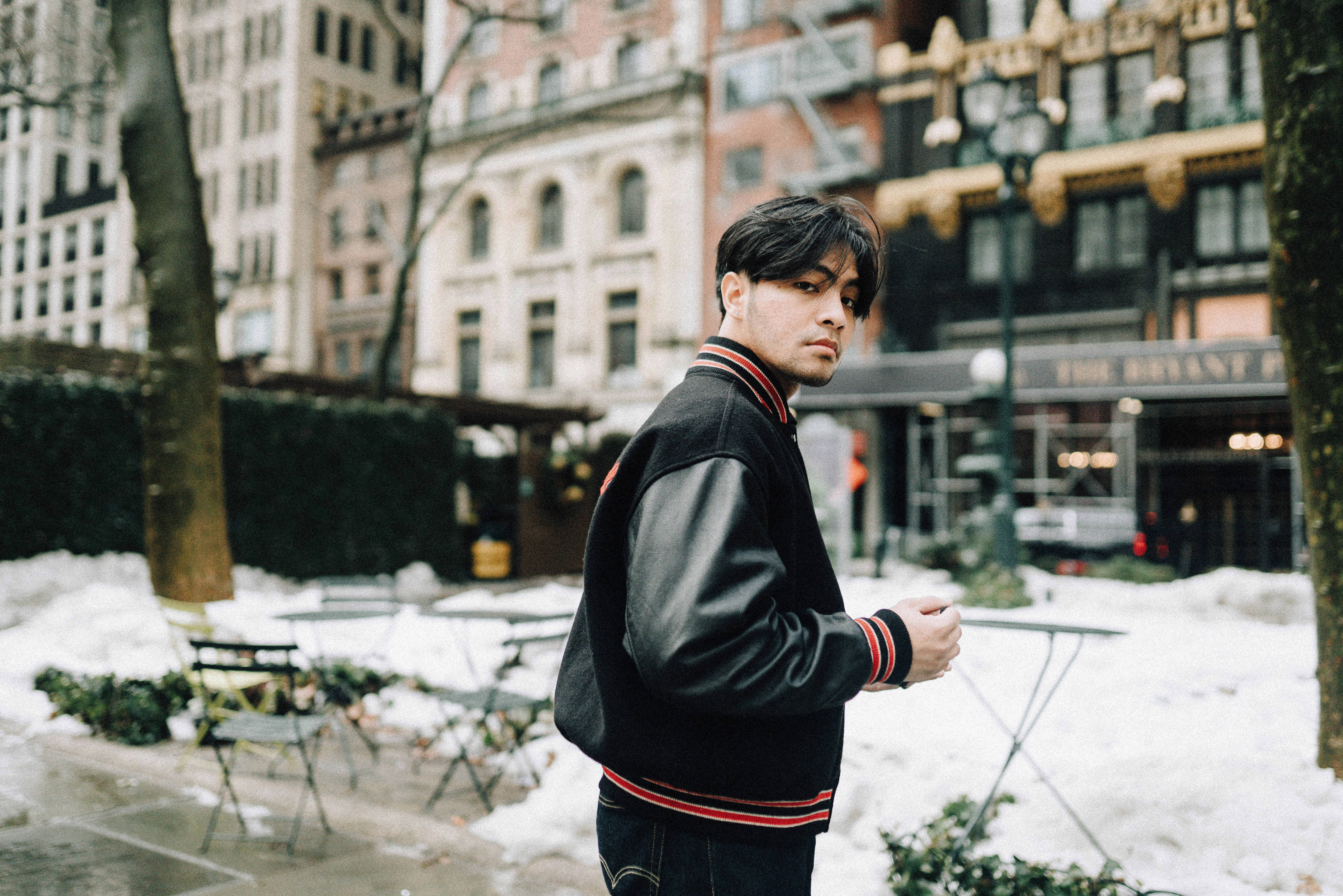 man in black jacket and red pants standing on gray concrete pavement during daytime