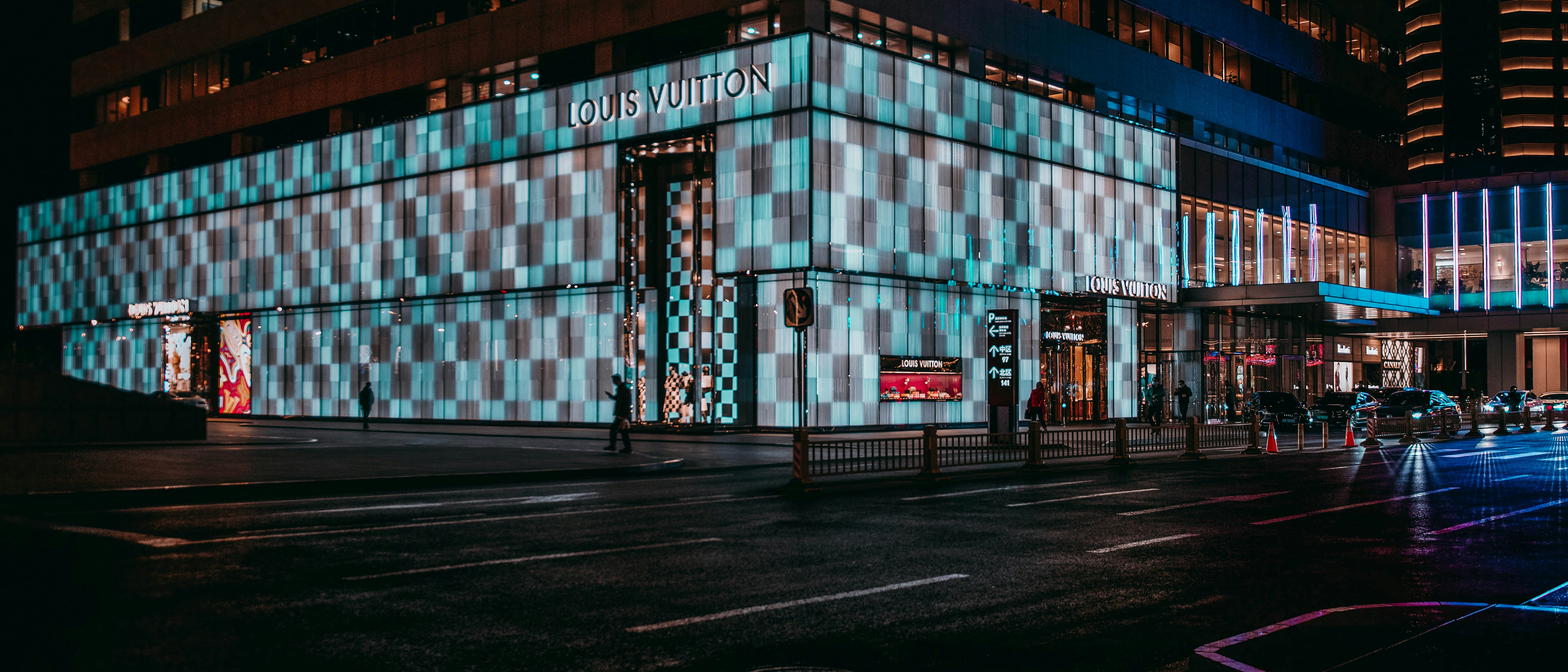 Louis Vuitton storefront illuminated with a dynamic light display, showcasing a contemporary design against a night backdrop.